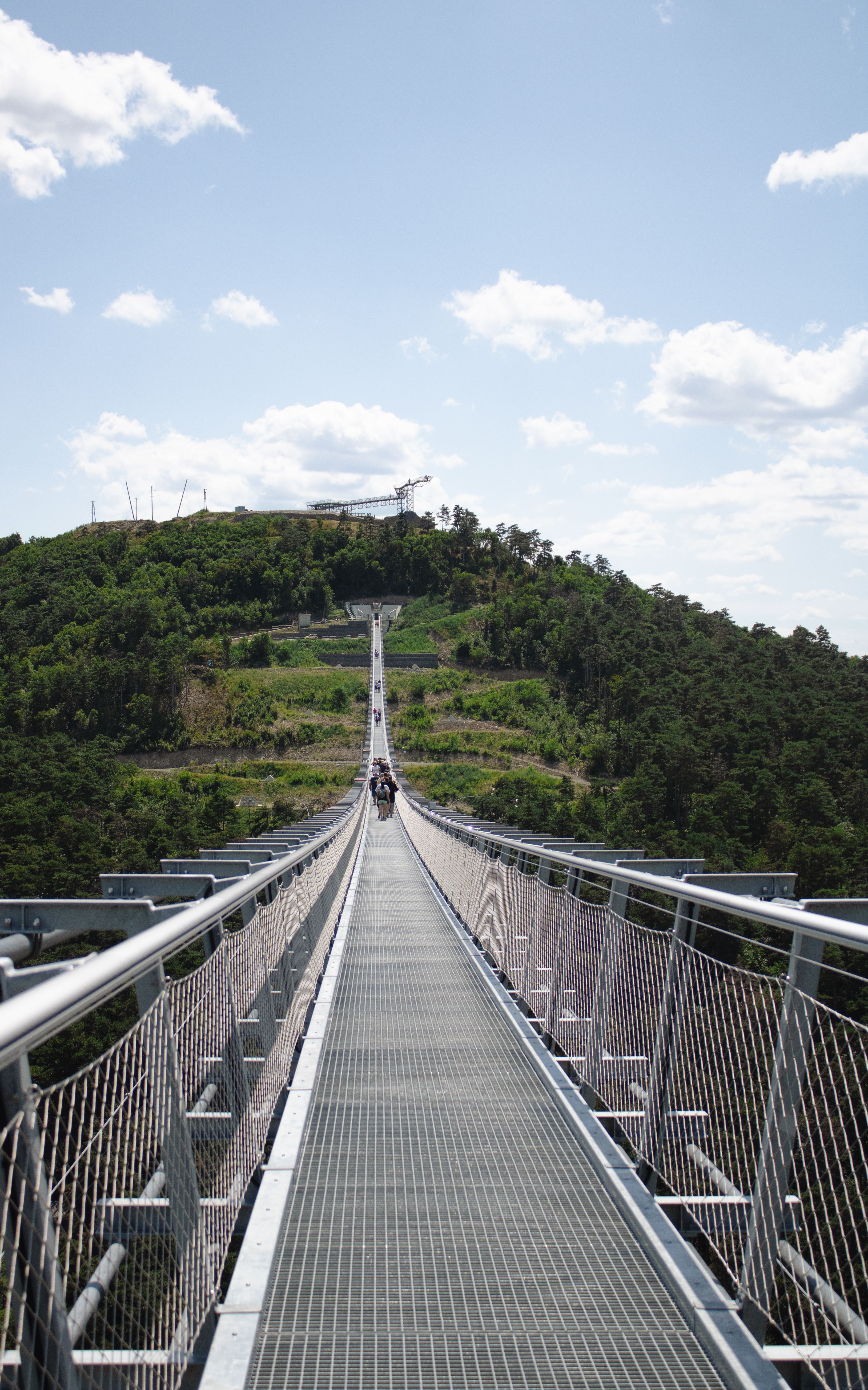 A suspension bridge over a hill with a view of the sky · Free Stock Photo