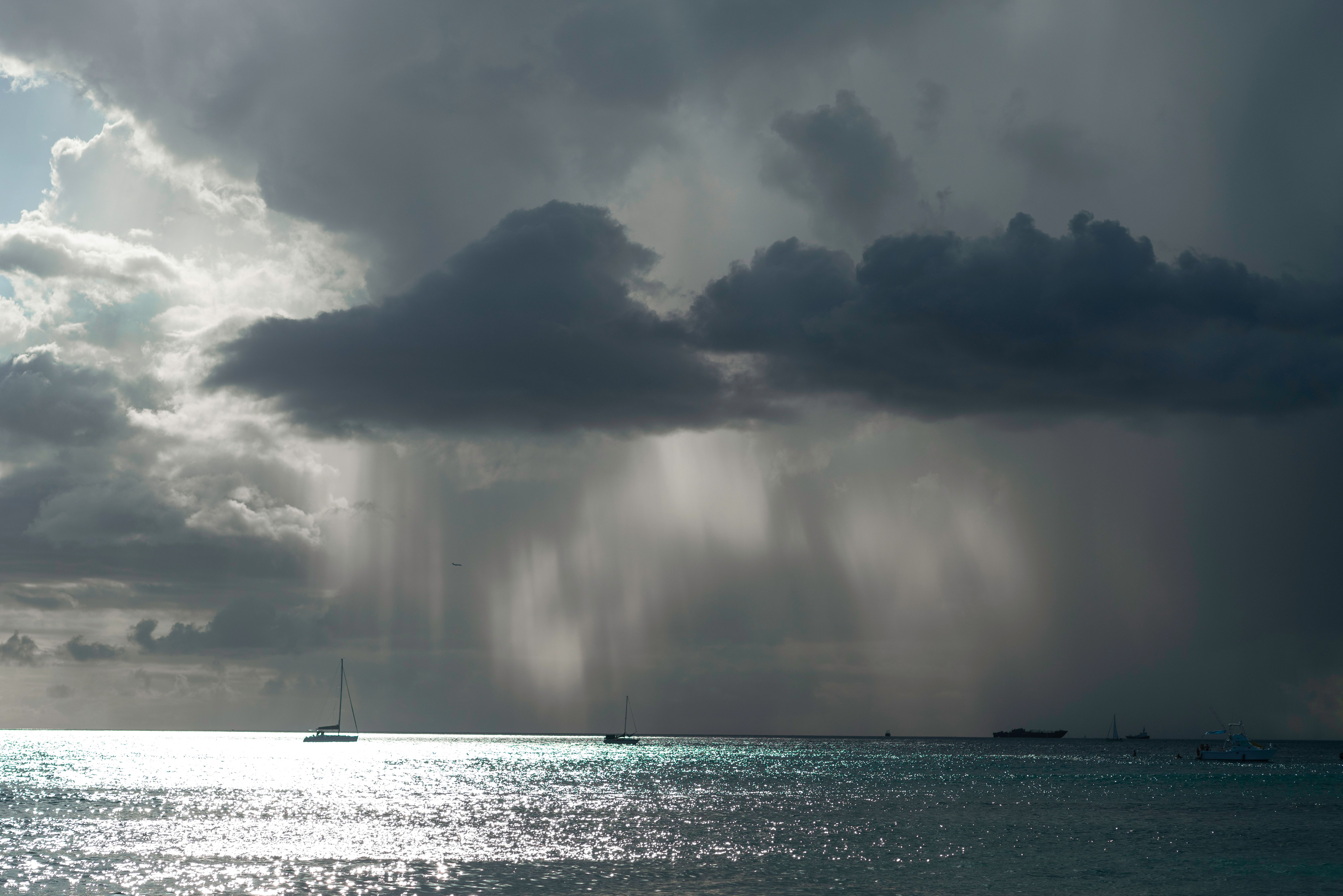 A boat is seen in the ocean under a dark cloud · Free Stock Photo
