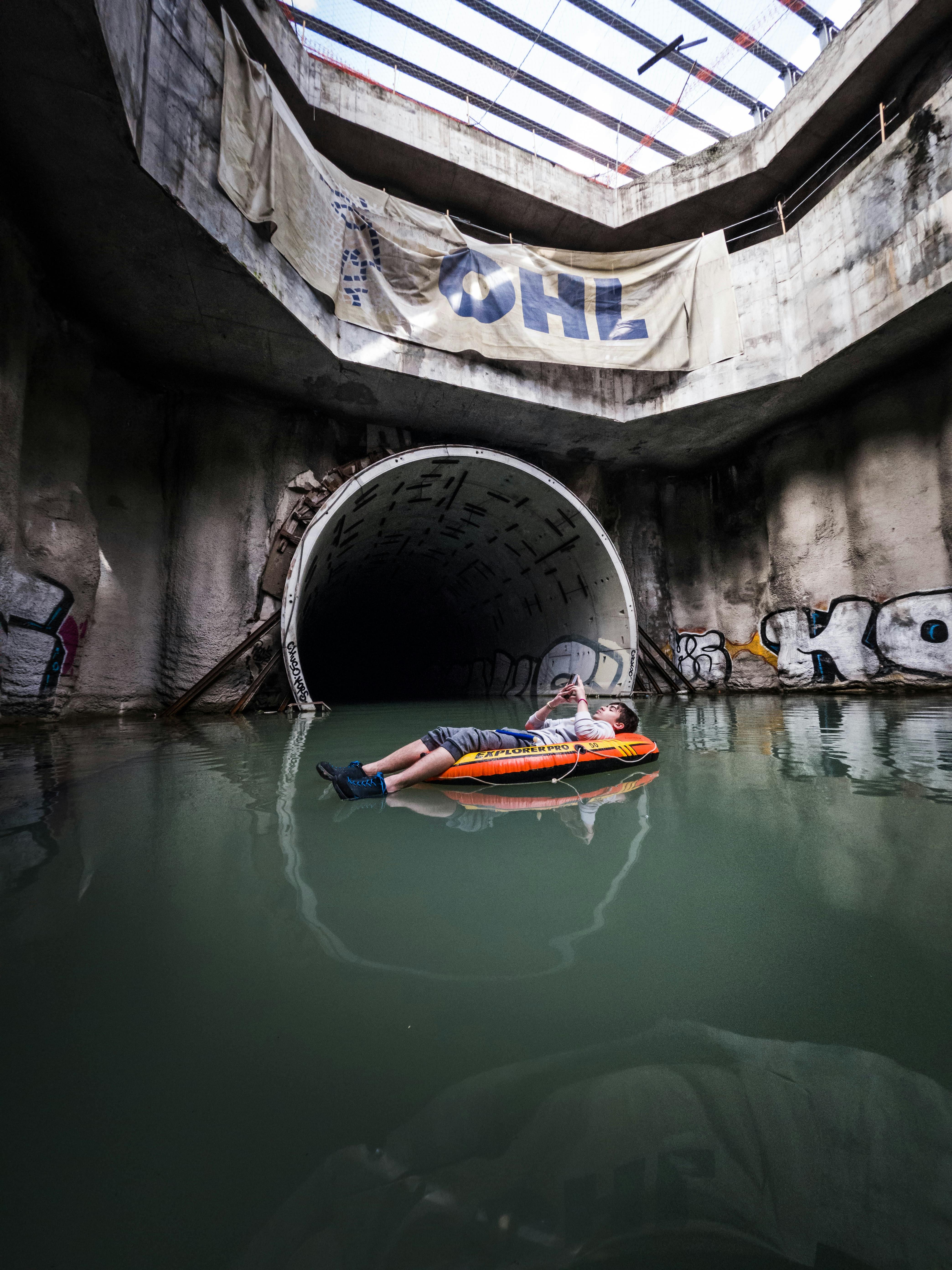 Man Lying Down on Pontoon on Water in Sewer · Free Stock Photo