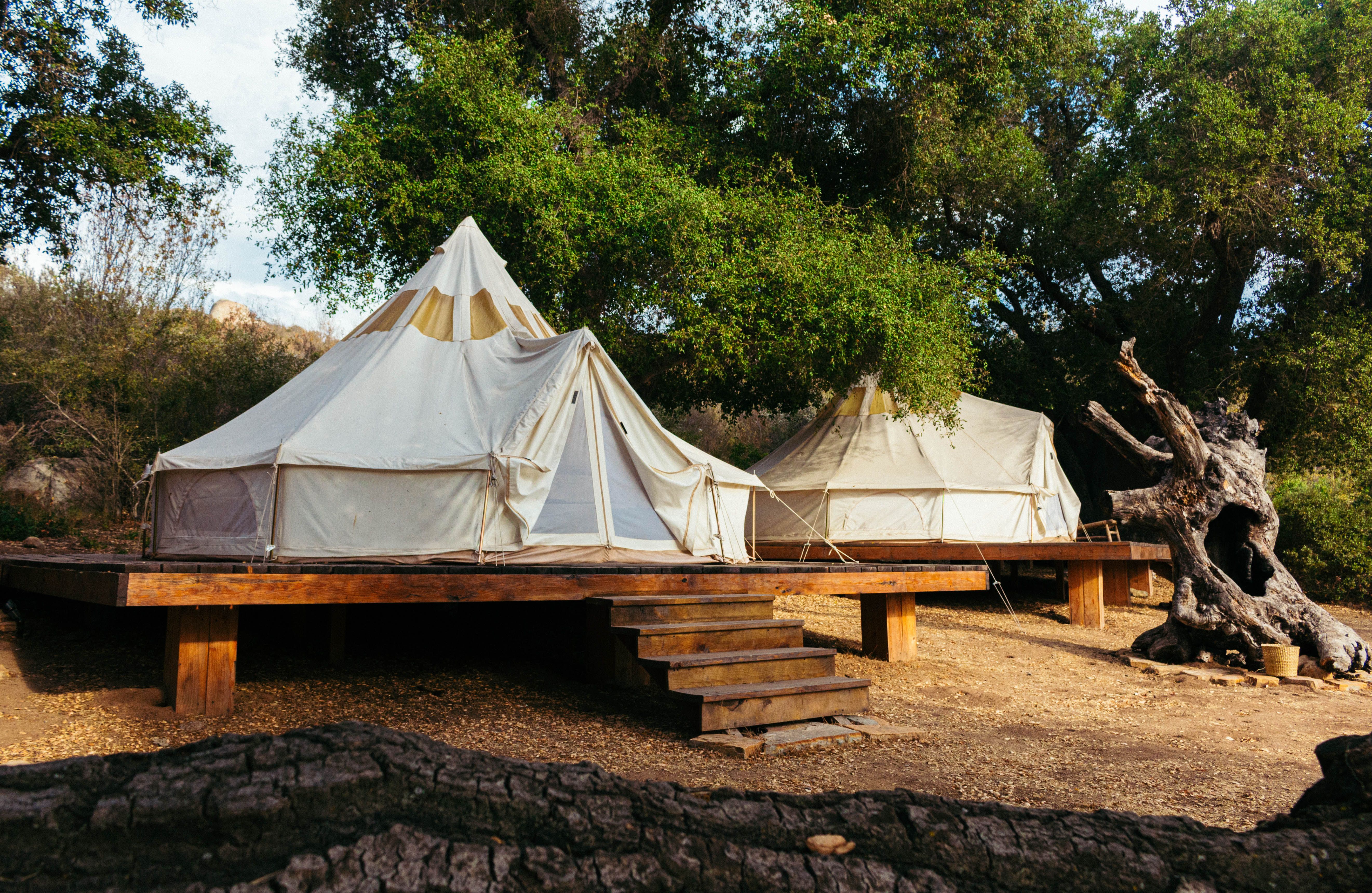 Two tents on wooden platforms in the middle of a field · Free Stock Photo