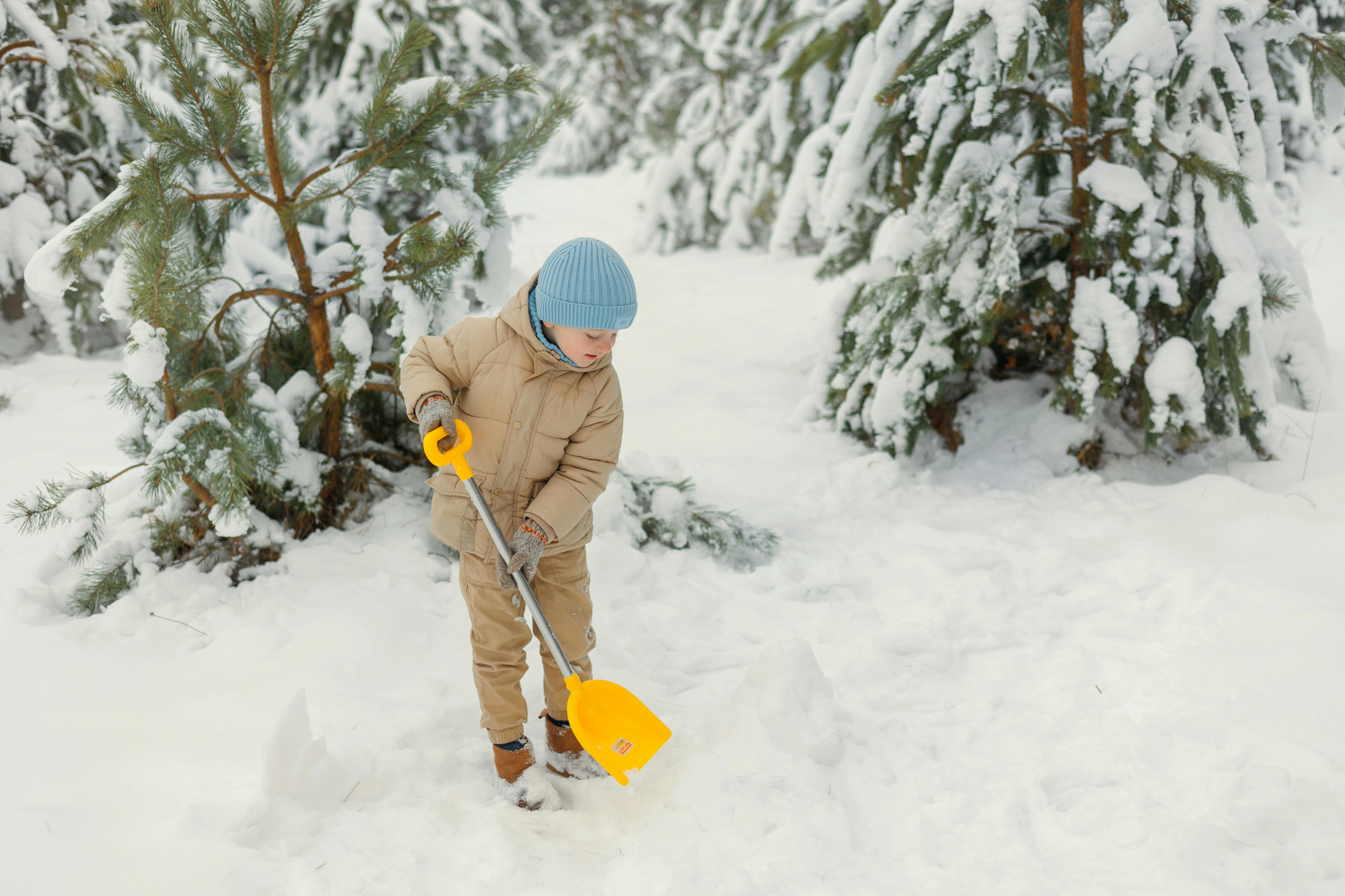 A child is digging in the snow with a shovel · Free Stock Photo