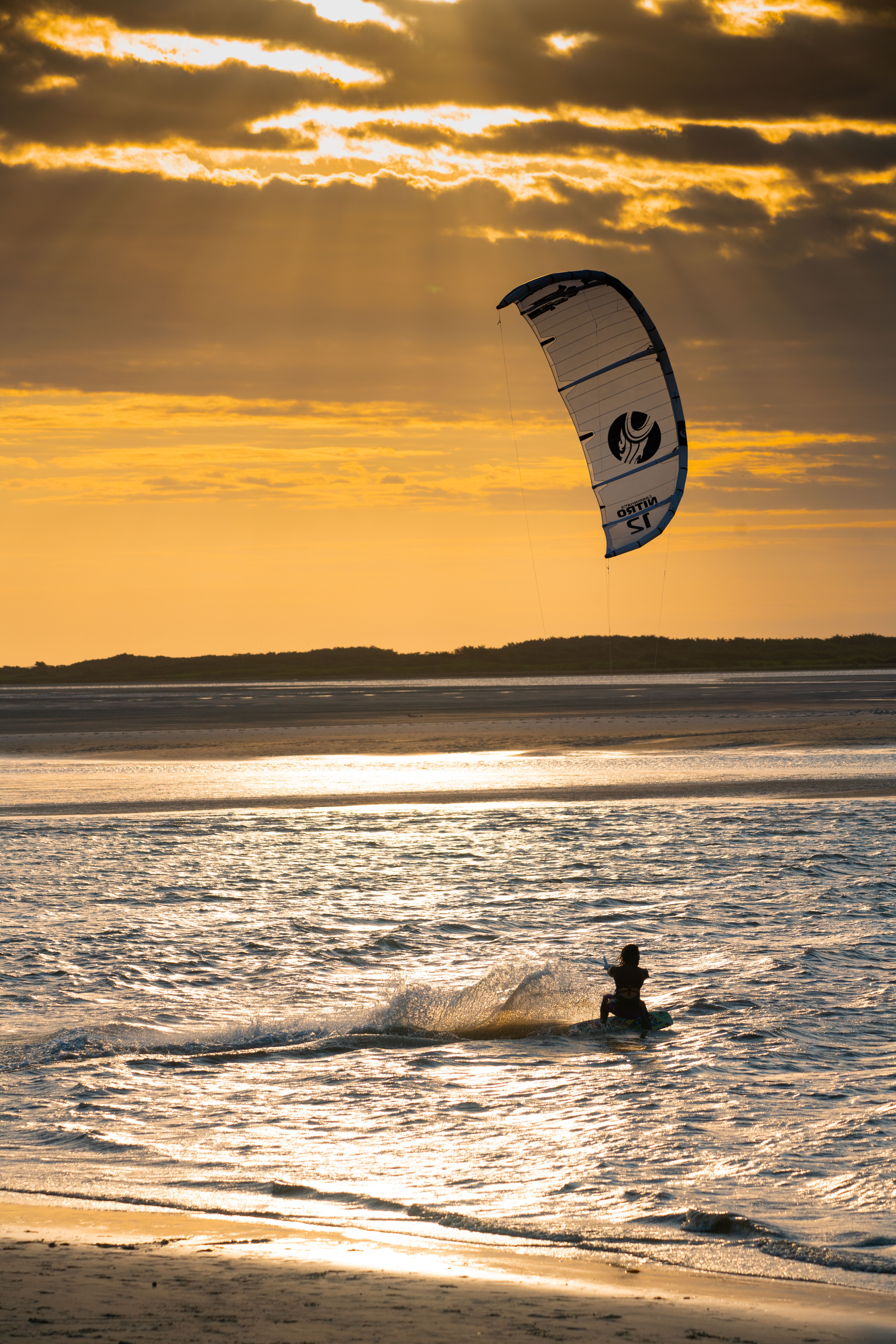 A person kite surfing in the ocean at sunset · Free Stock Photo