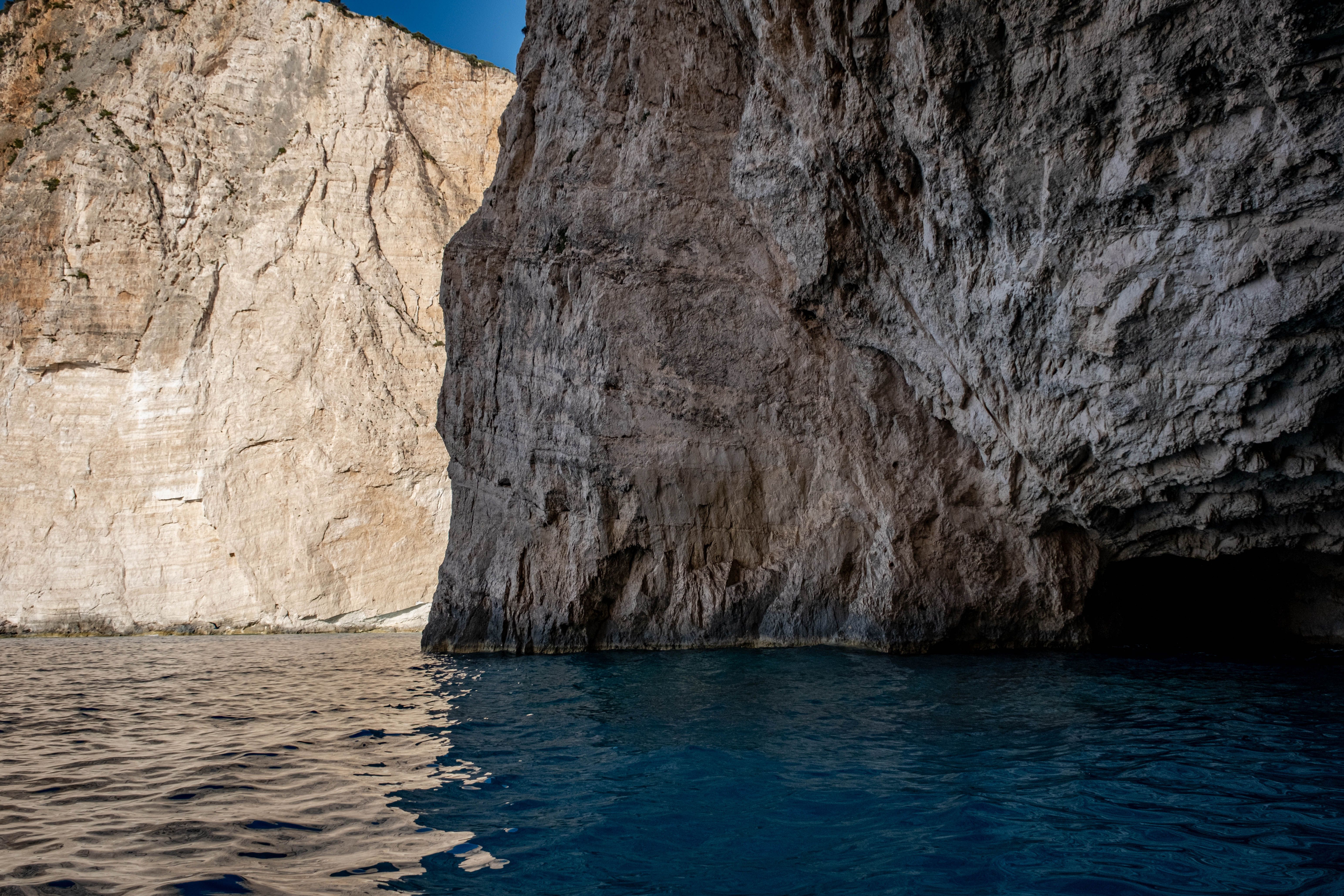 The blue water is surrounded by cliffs and rocks · Free Stock Photo