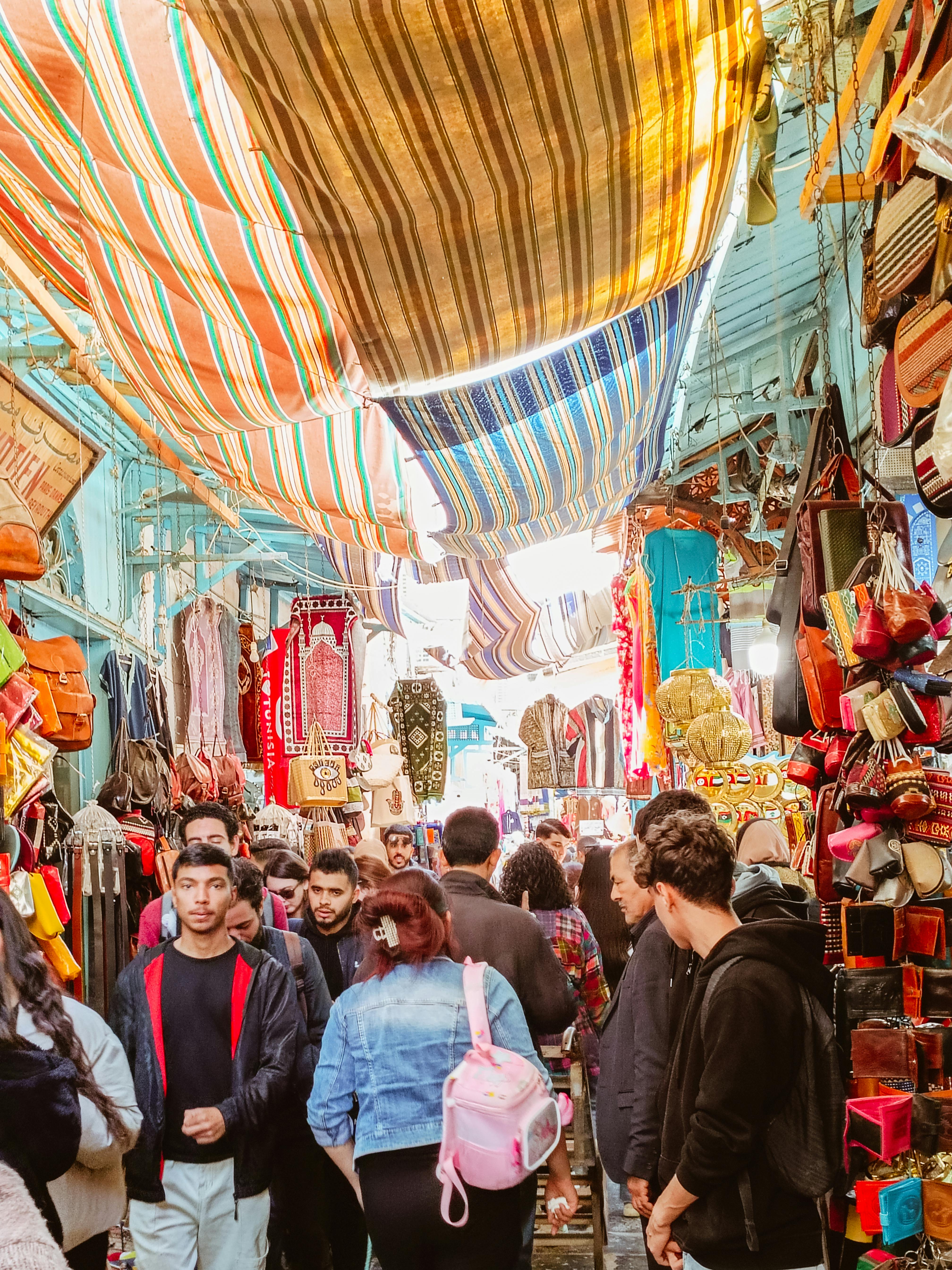 People walking through a market with colorful cloths · Free Stock Photo