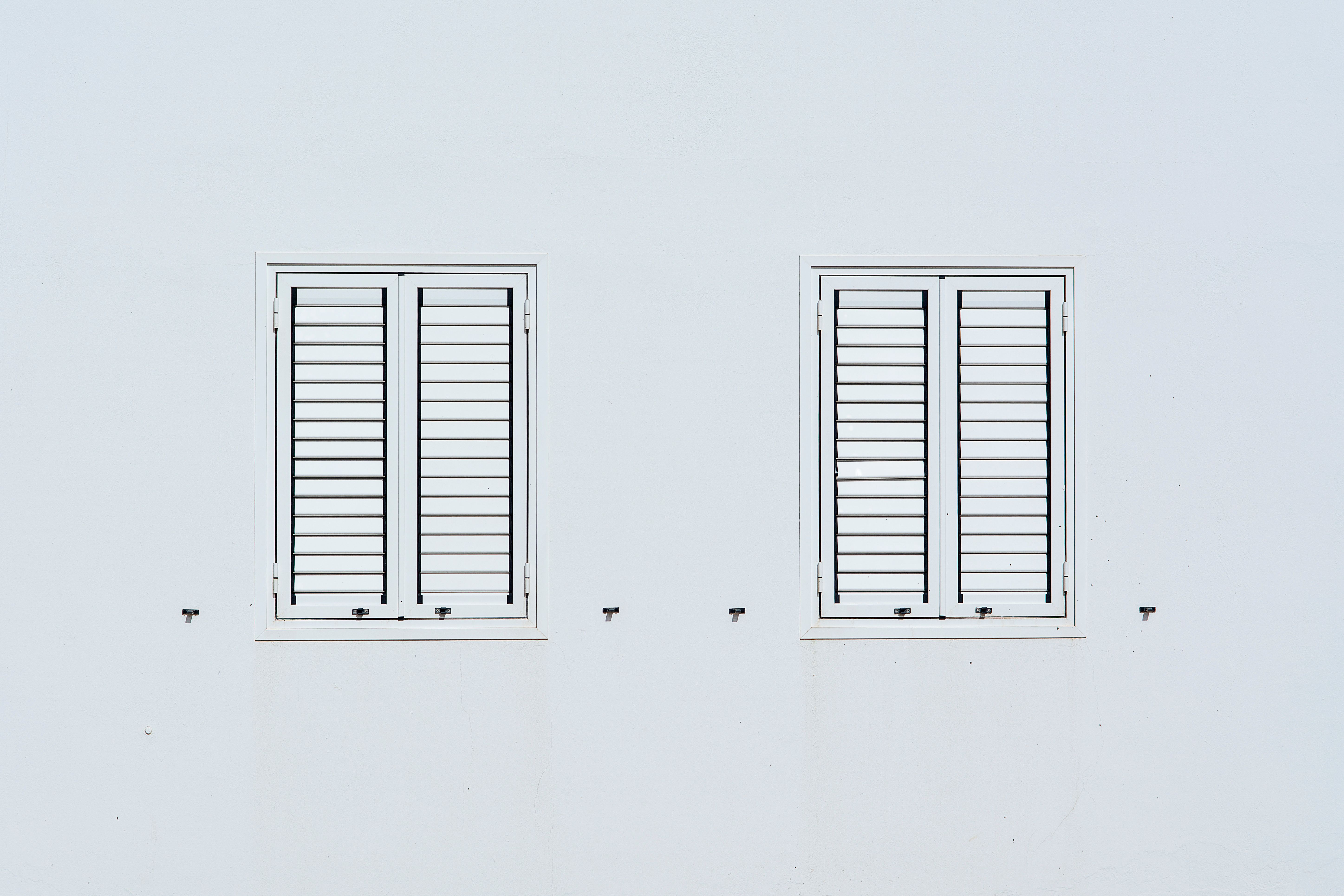 Two white windows with shutters on a white wall · Free Stock Photo