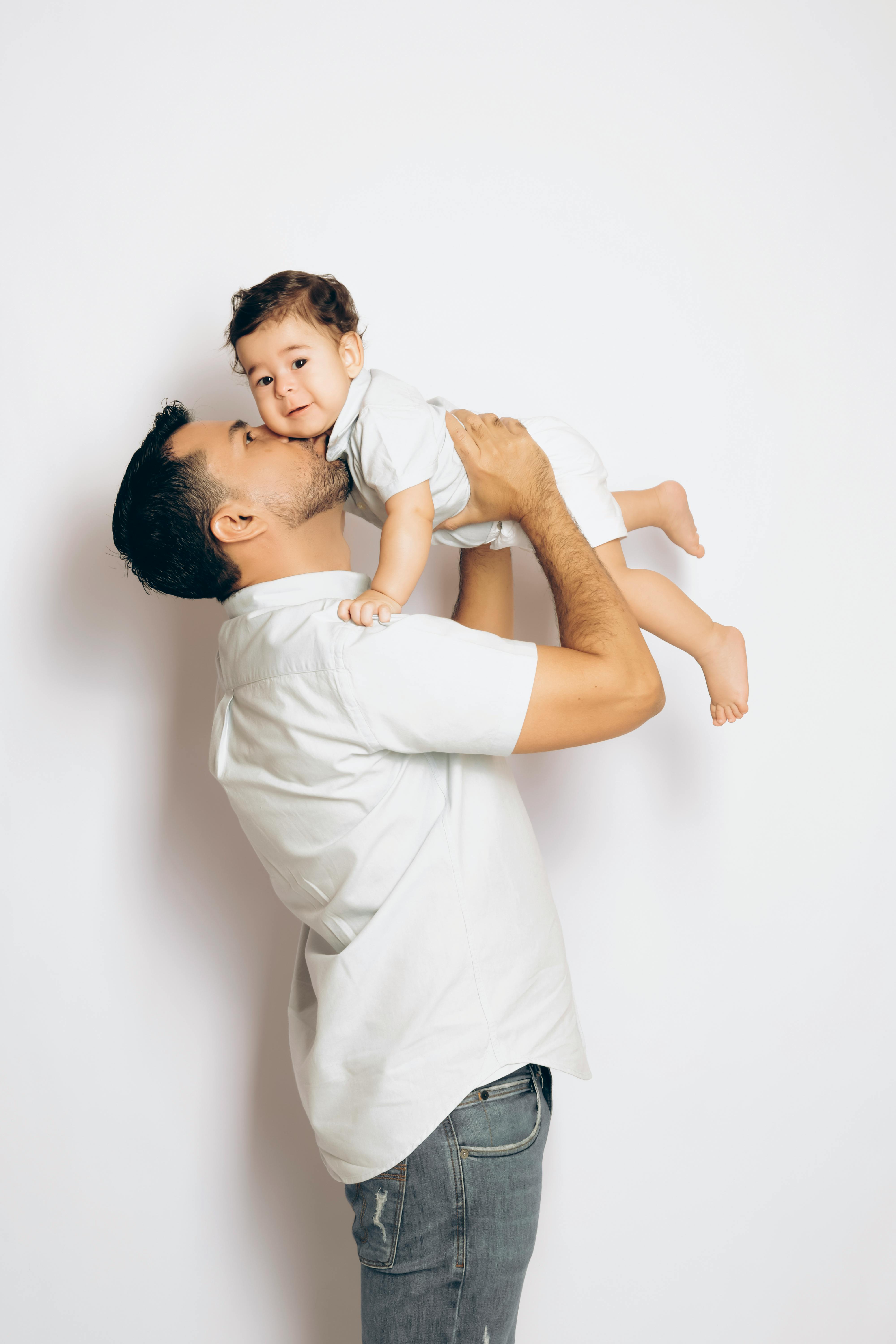 A man holding a baby in the air · Free Stock Photo