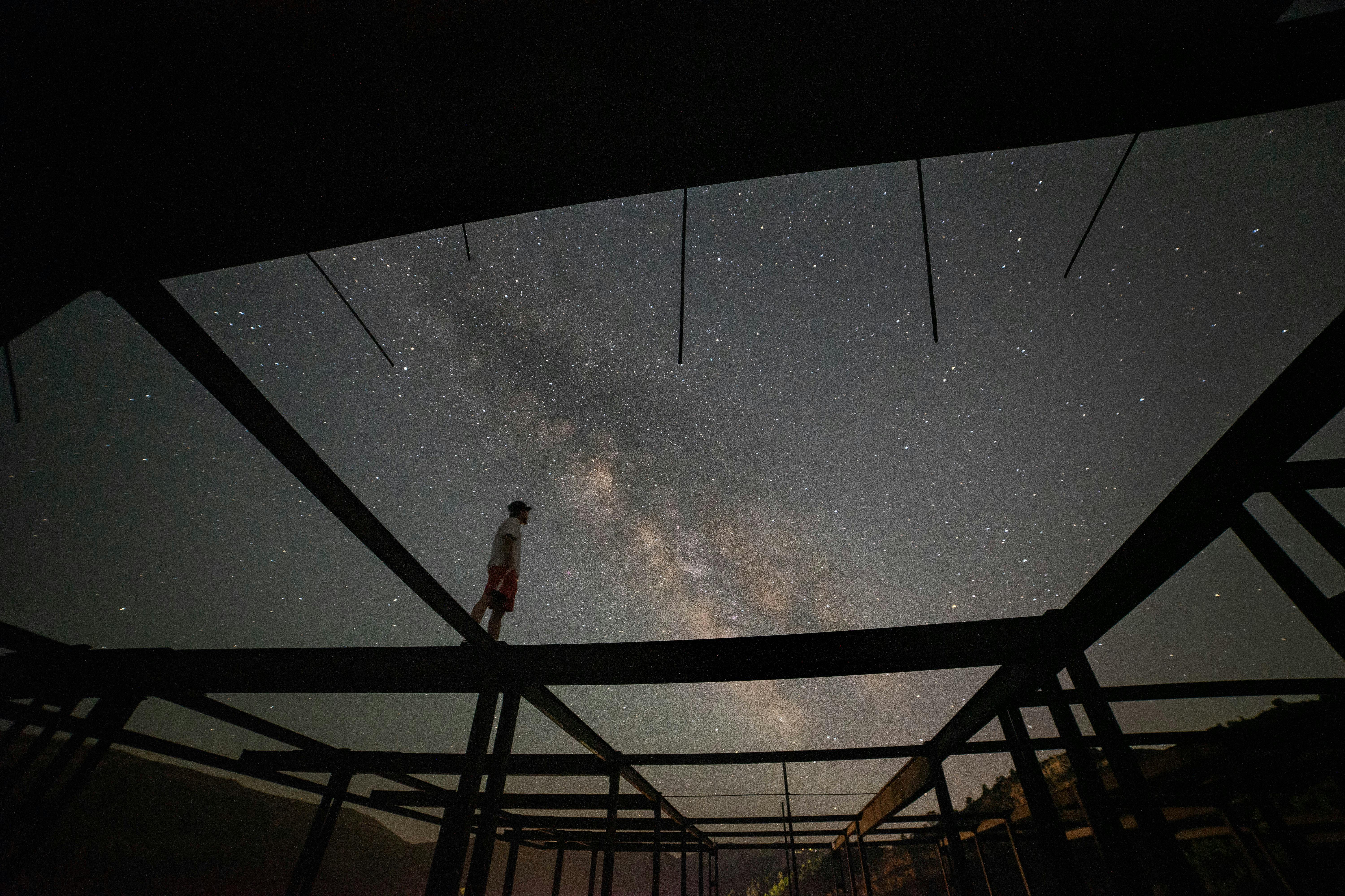 A man standing on a roof looking up at the sky · Free Stock Photo