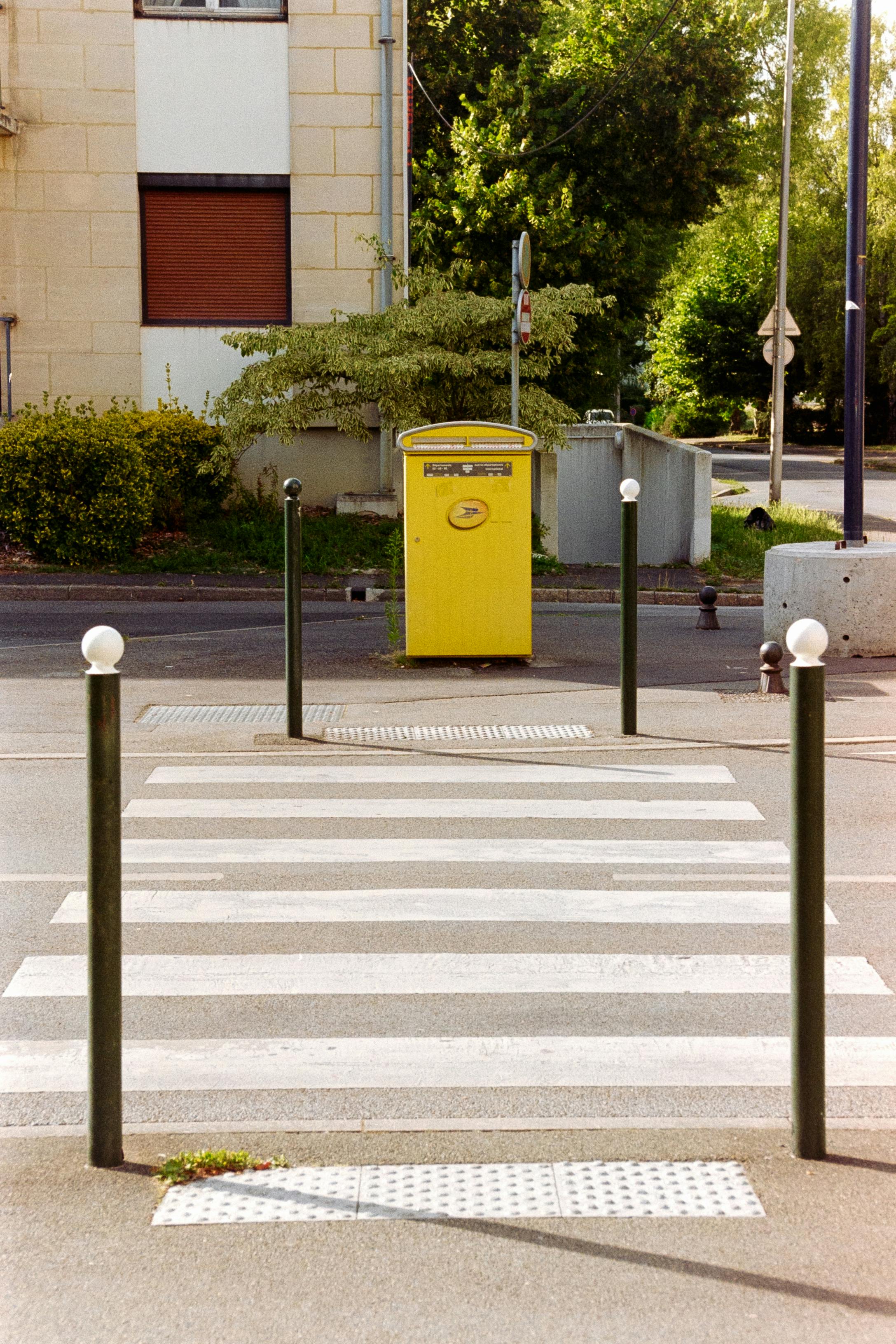 A yellow box on a crosswalk with poles · Free Stock Photo