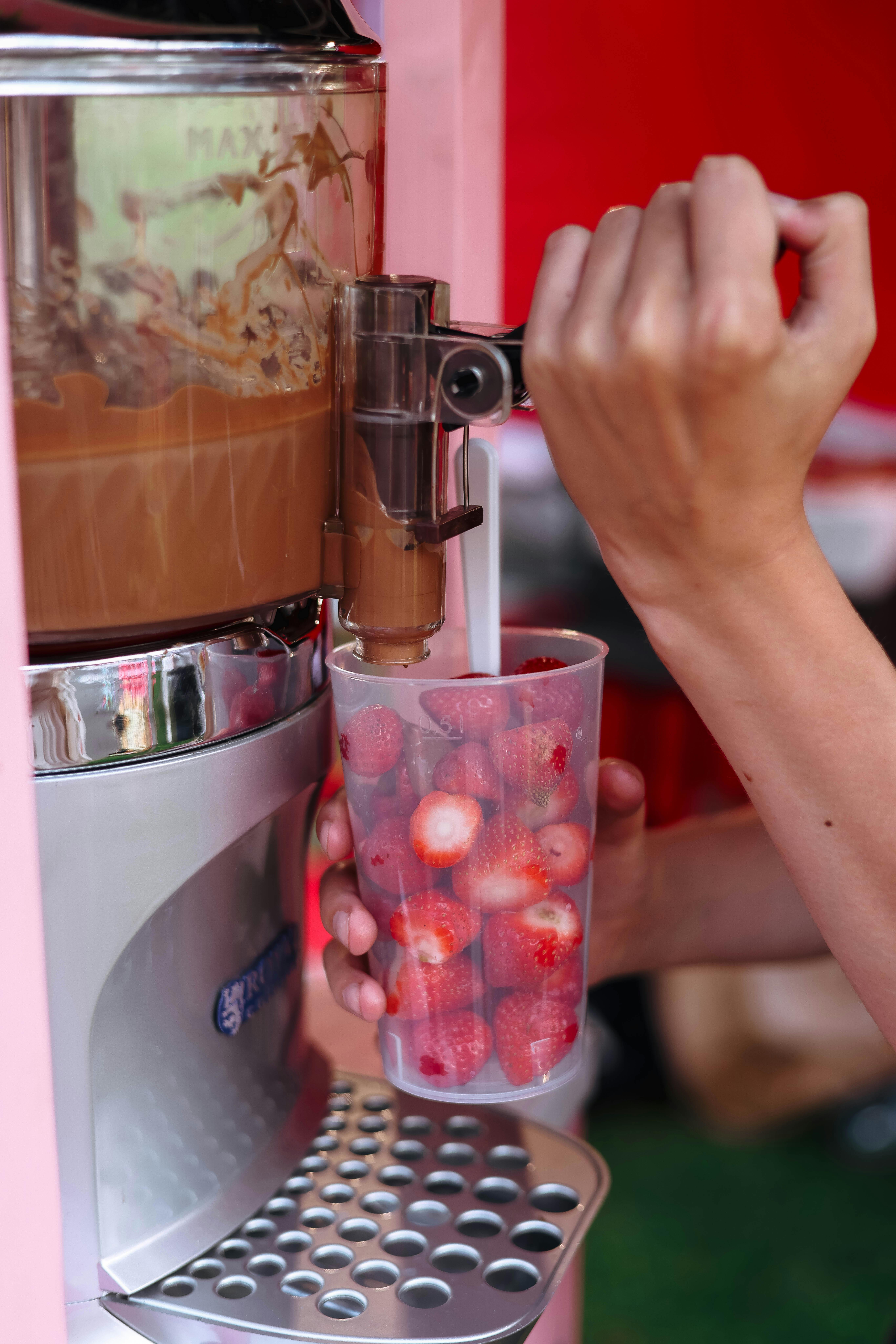 A person is pouring a drink into a strawberry machine · Free Stock Photo