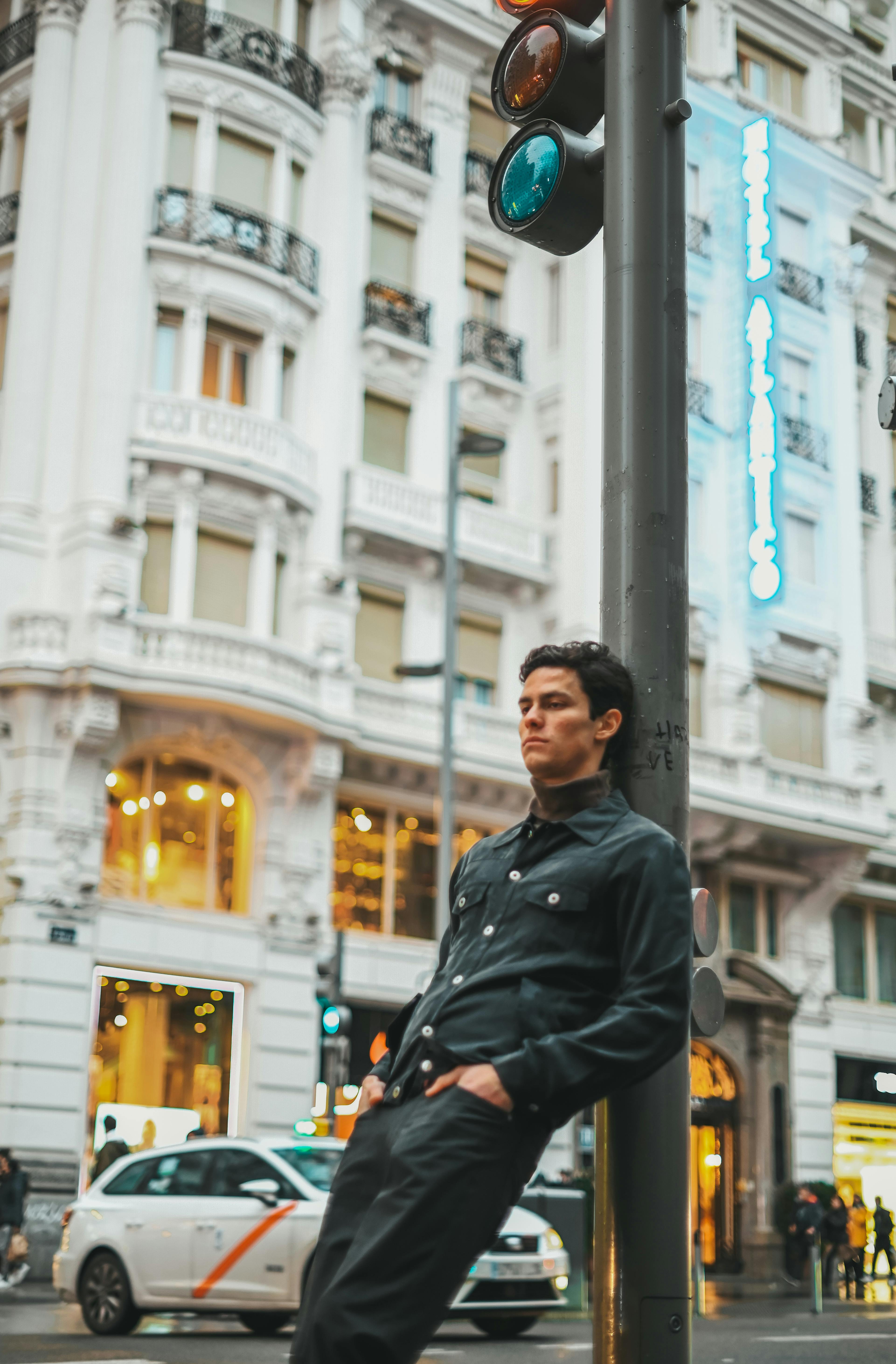 A man leaning against a traffic light · Free Stock Photo