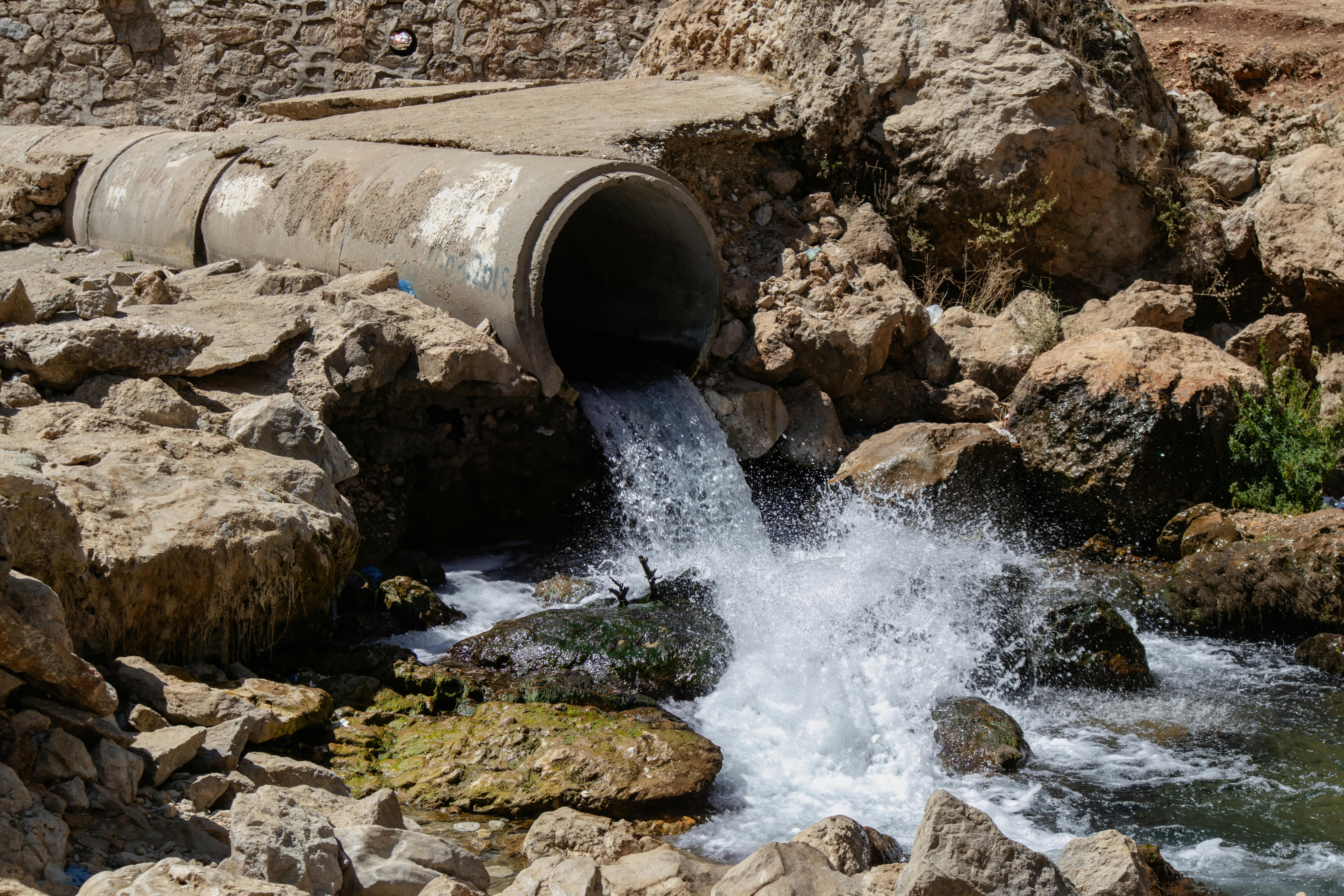 A pipe is running through a stream with water flowing out · Free Stock ...