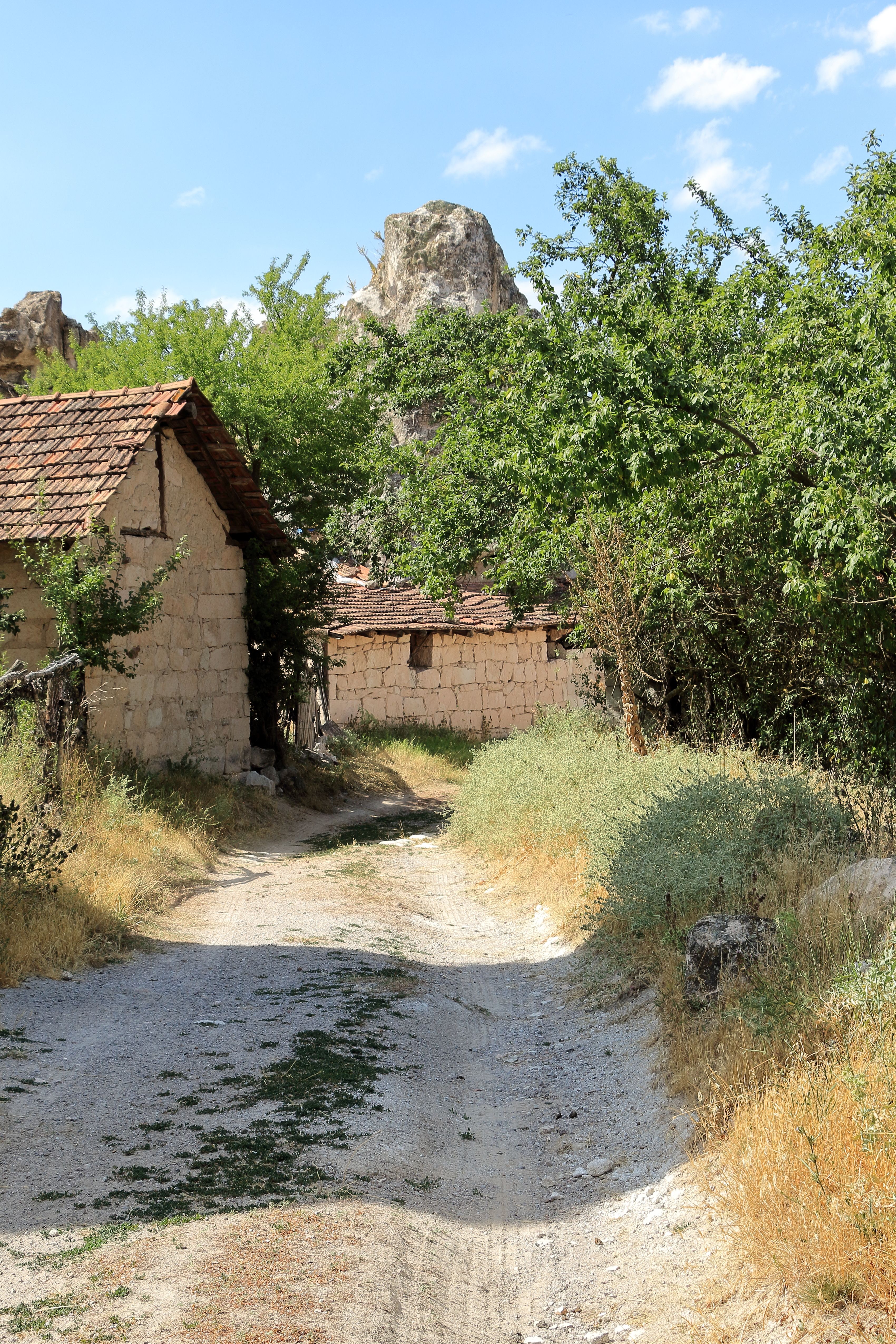 A dirt road leading to a stone building · Free Stock Photo