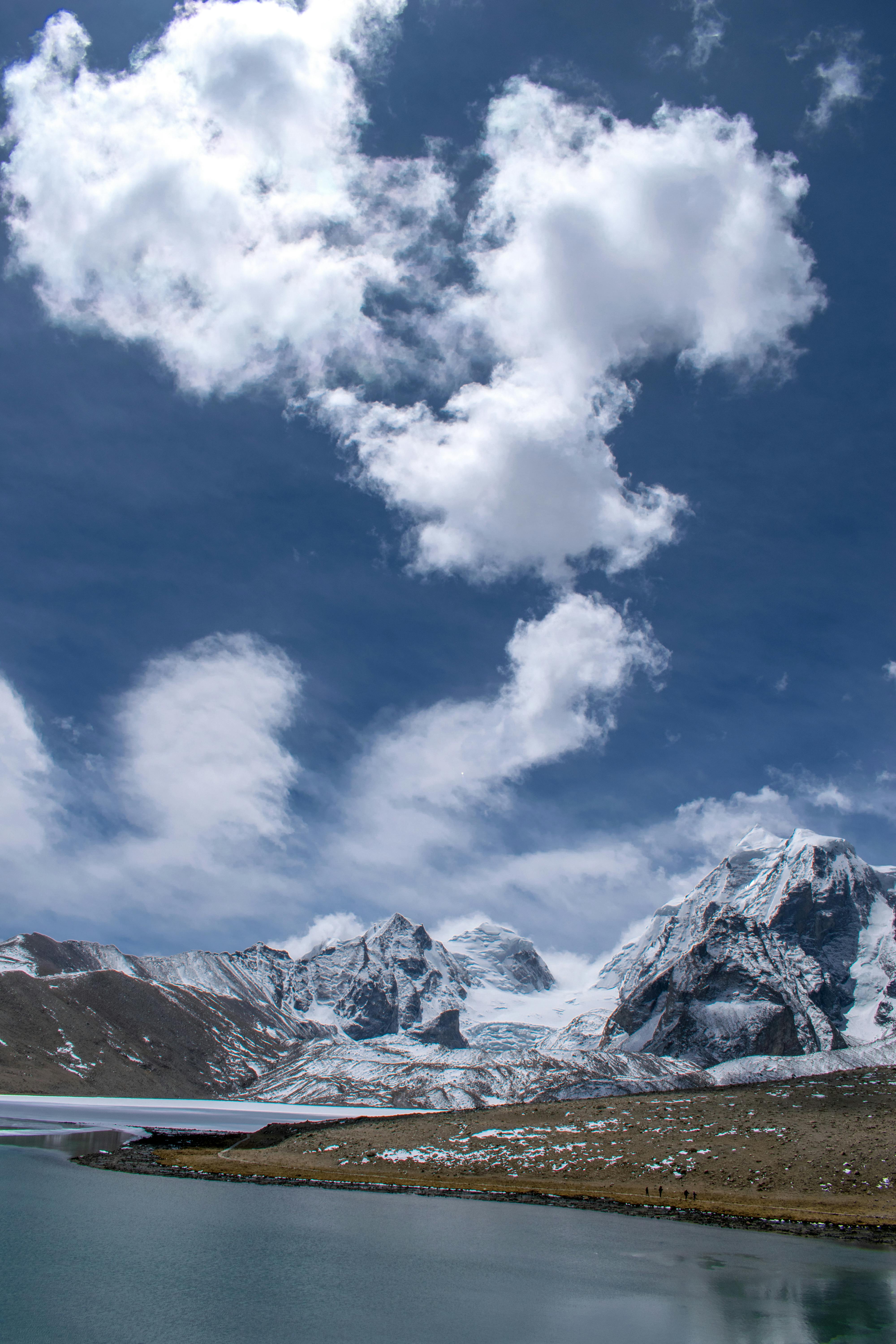 Photo of Snow Capped Mountains Under Cloudy Sky · Free Stock Photo