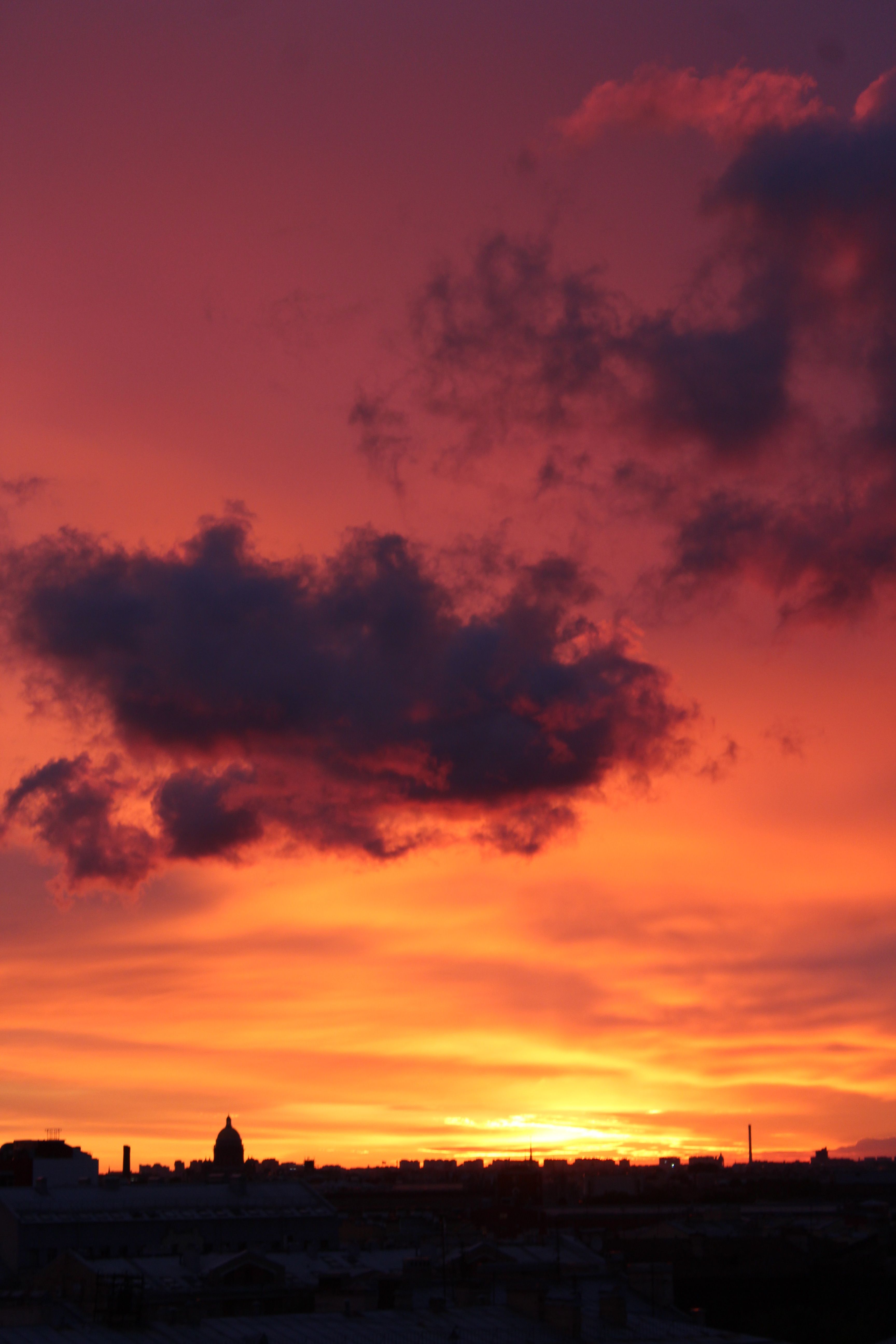 A sunset with clouds and buildings in the background · Free Stock Photo
