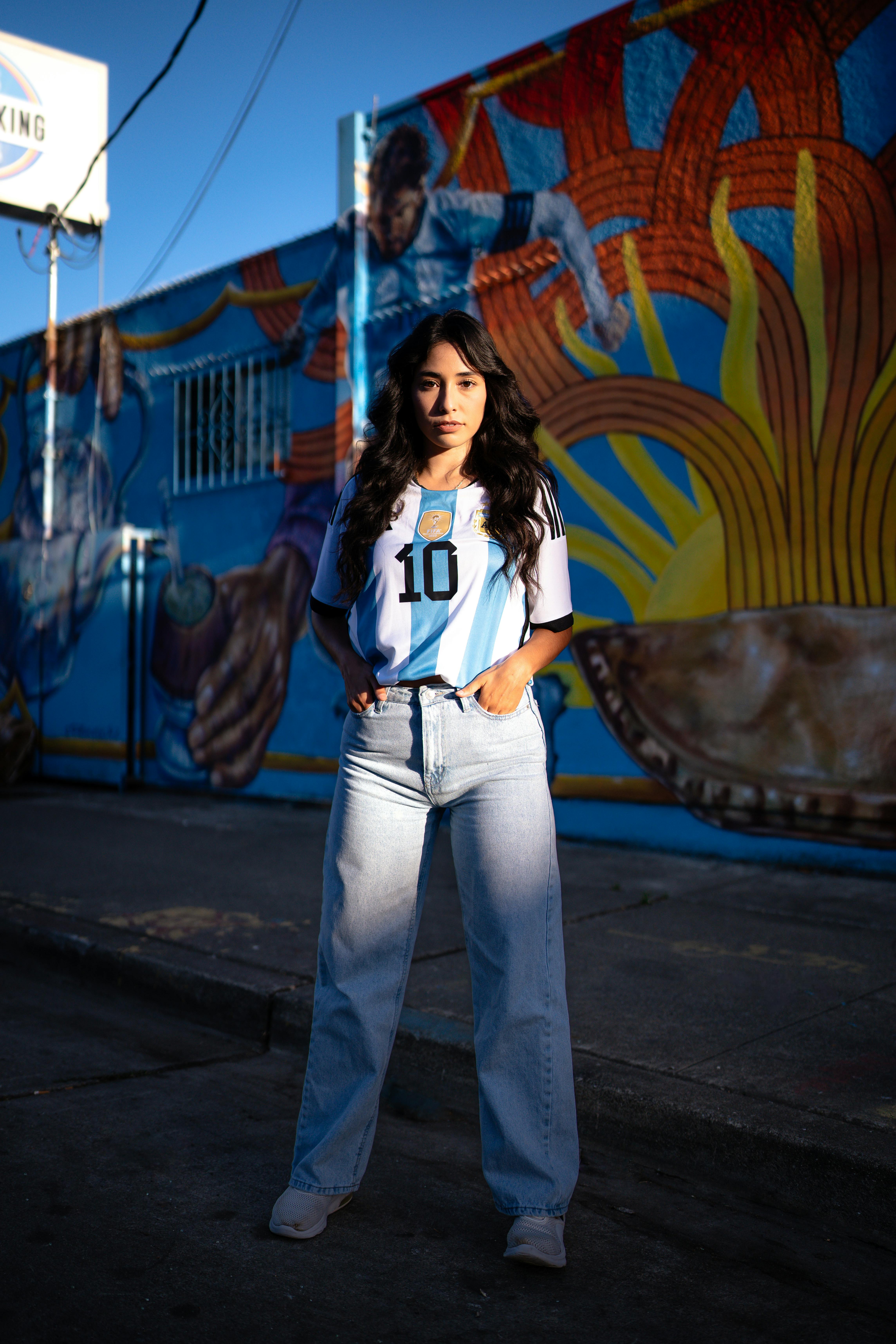 A woman in jeans and a white shirt standing in front of a mural · Free ...