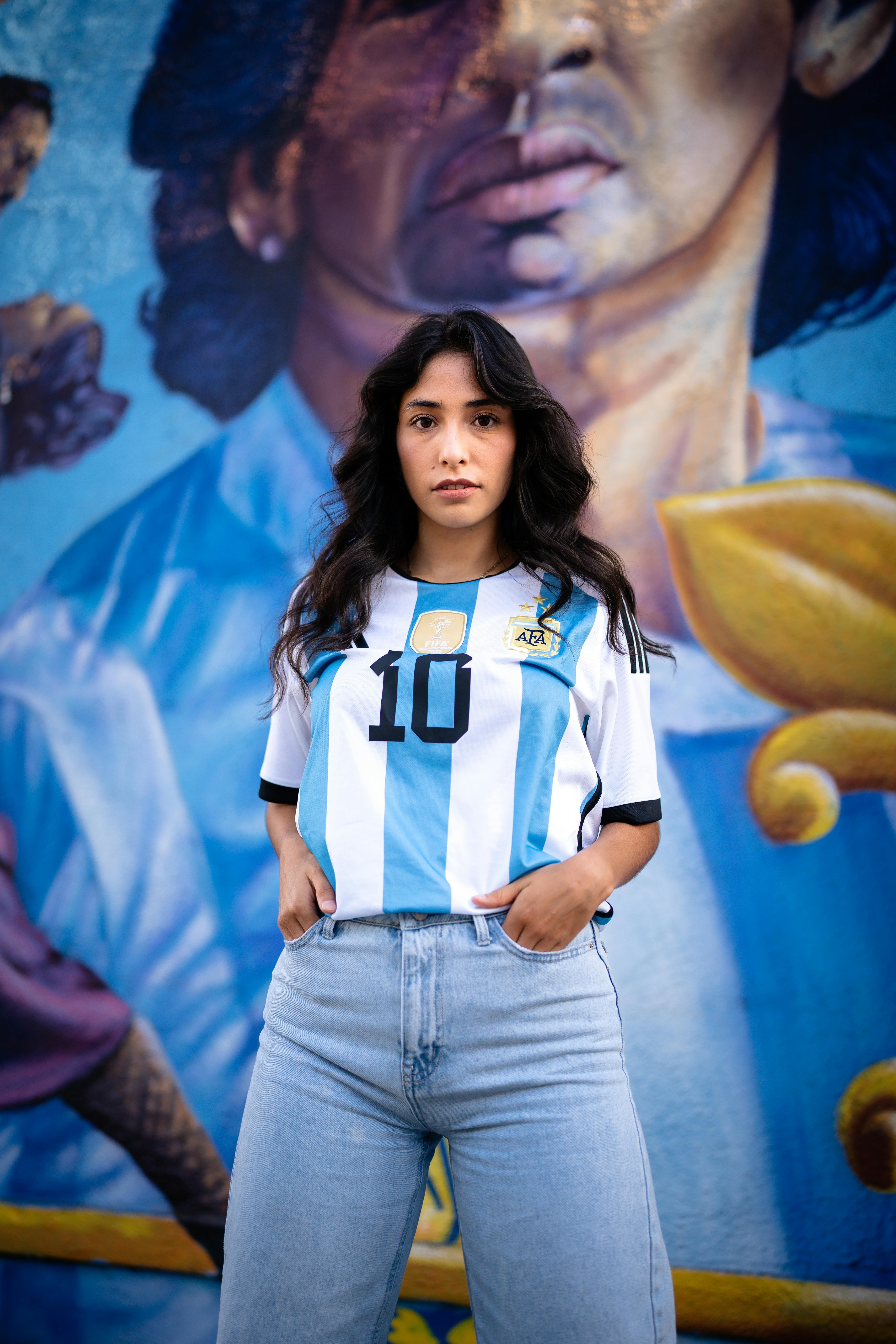 A woman in jeans and a soccer jersey standing in front of a mural ...