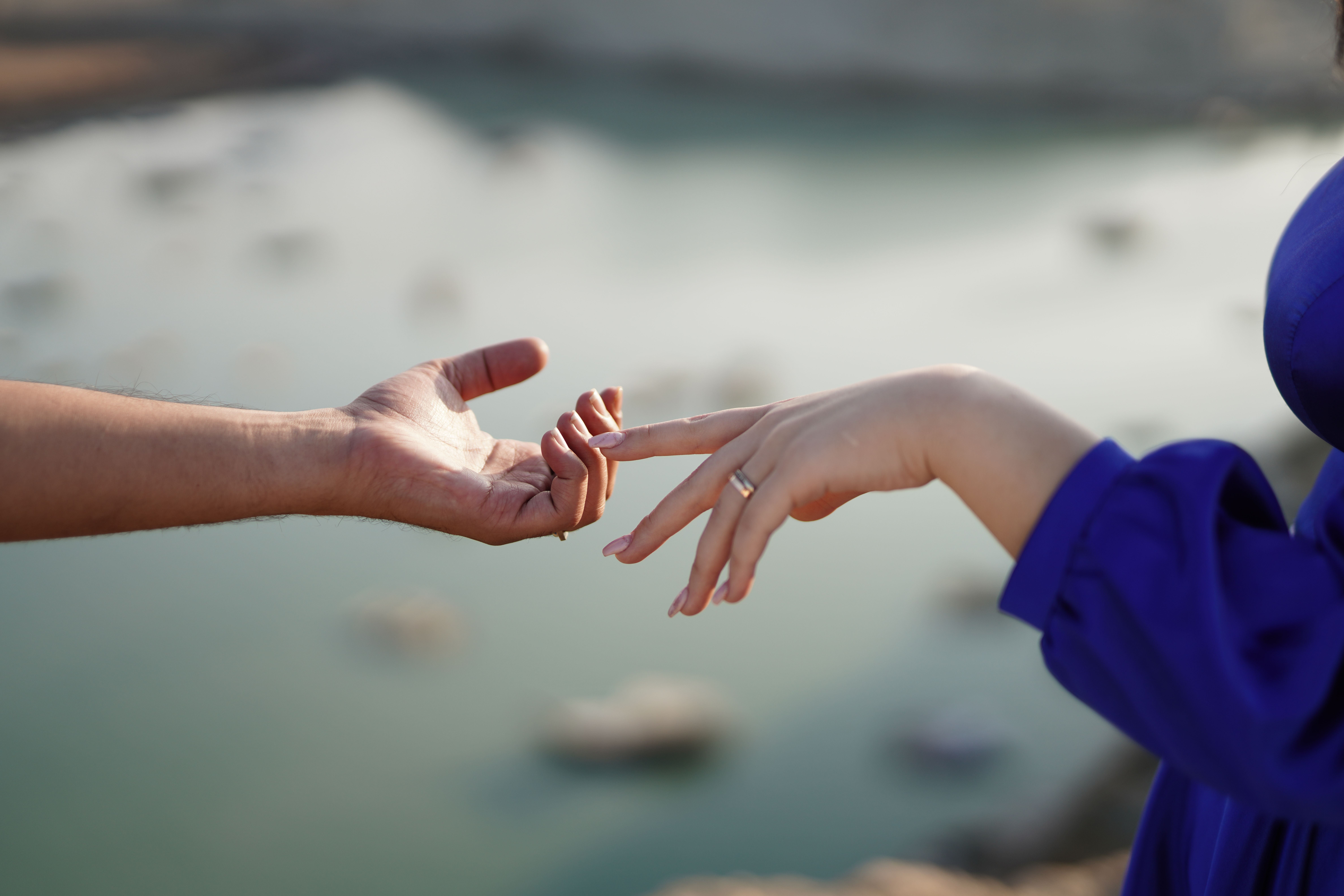 A couple holding hands in front of a body of water · Free Stock Photo