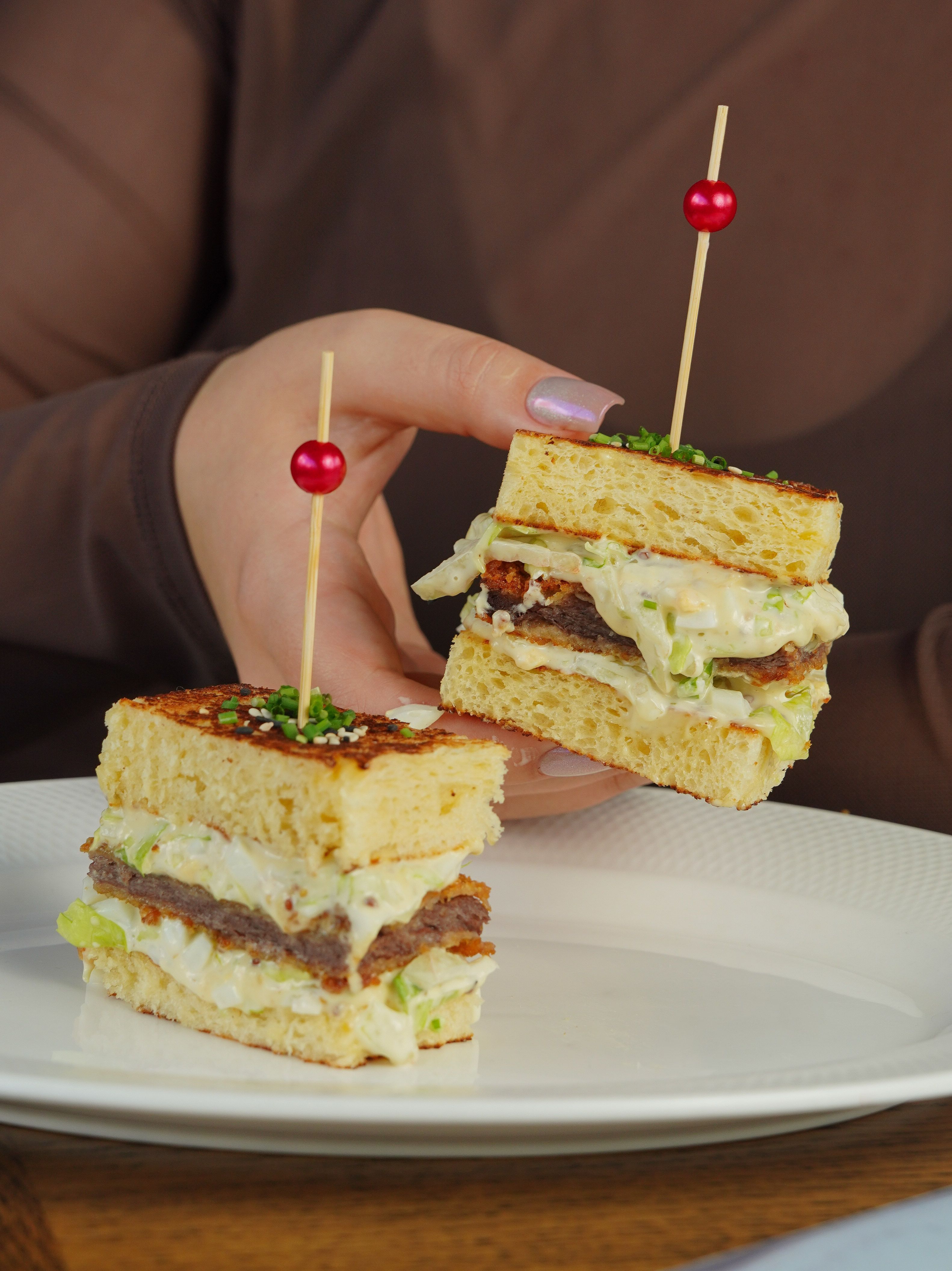 A person holding a sandwich with a toothpick · Free Stock Photo
