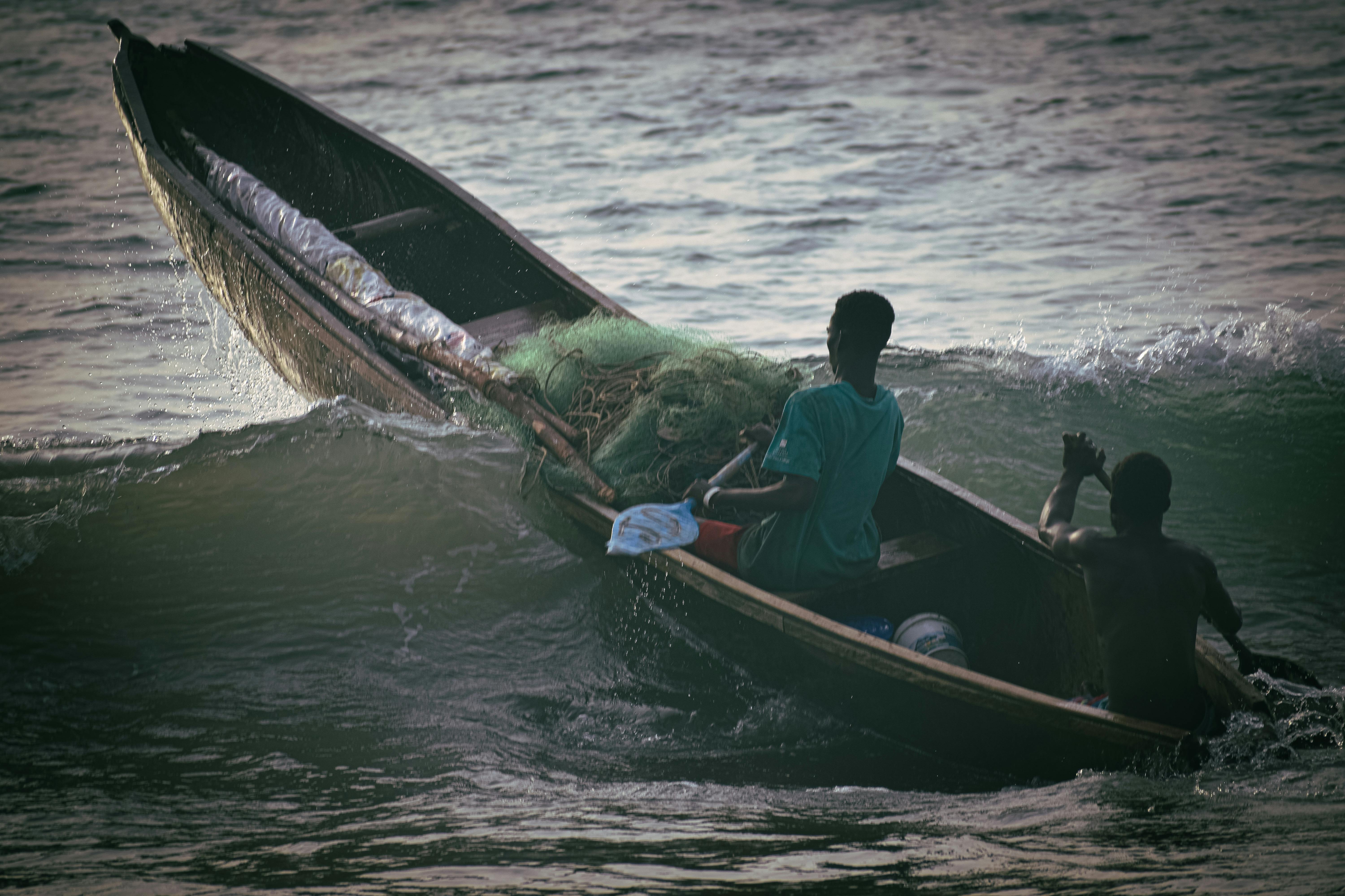 A Man Rowing A Small Boat With a Sail · Free Stock Photo