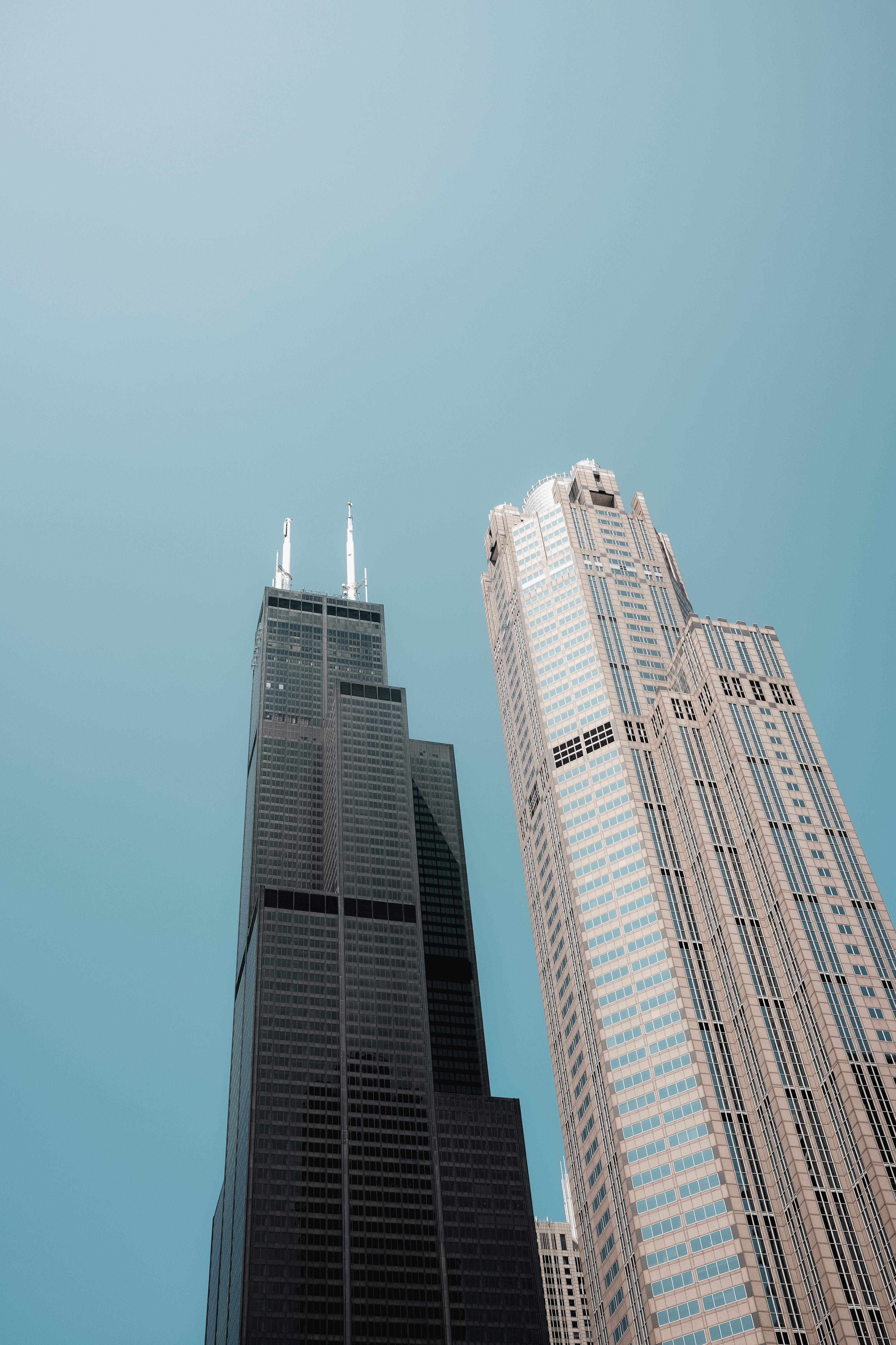 Two tall buildings with a blue sky in the background · Free Stock Photo