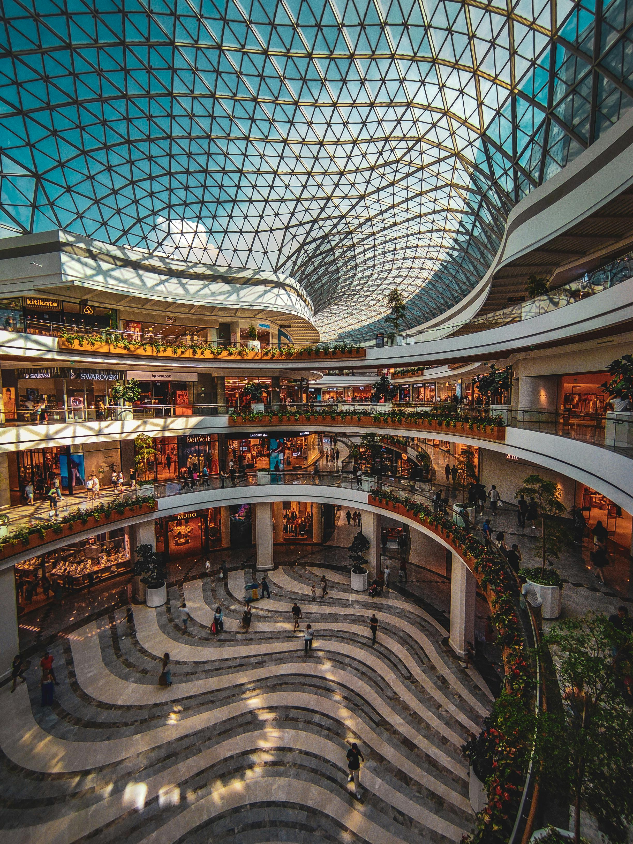 The inside of a shopping mall with a glass roof · Free Stock Photo