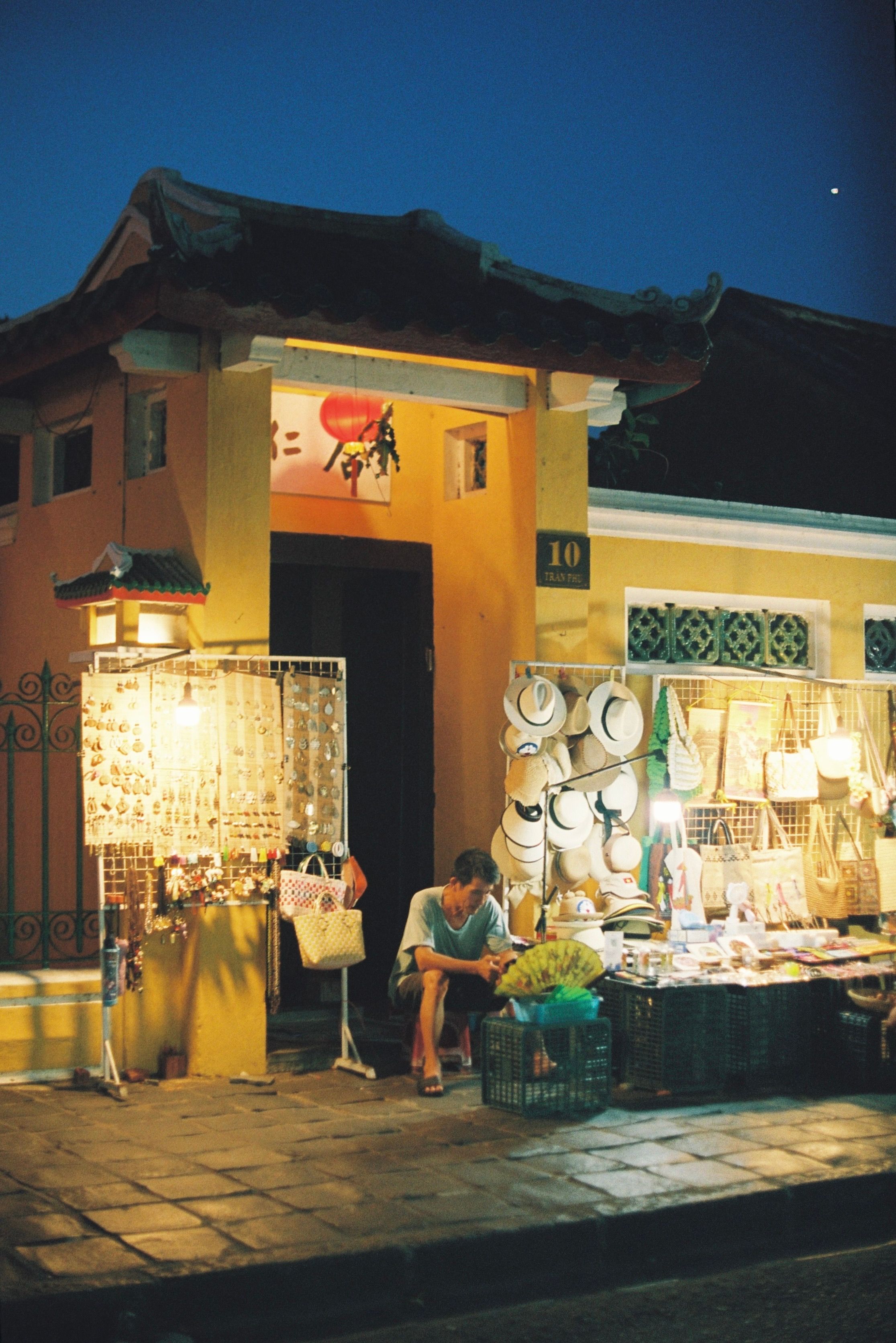 A man is sitting outside a shop at night · Free Stock Photo