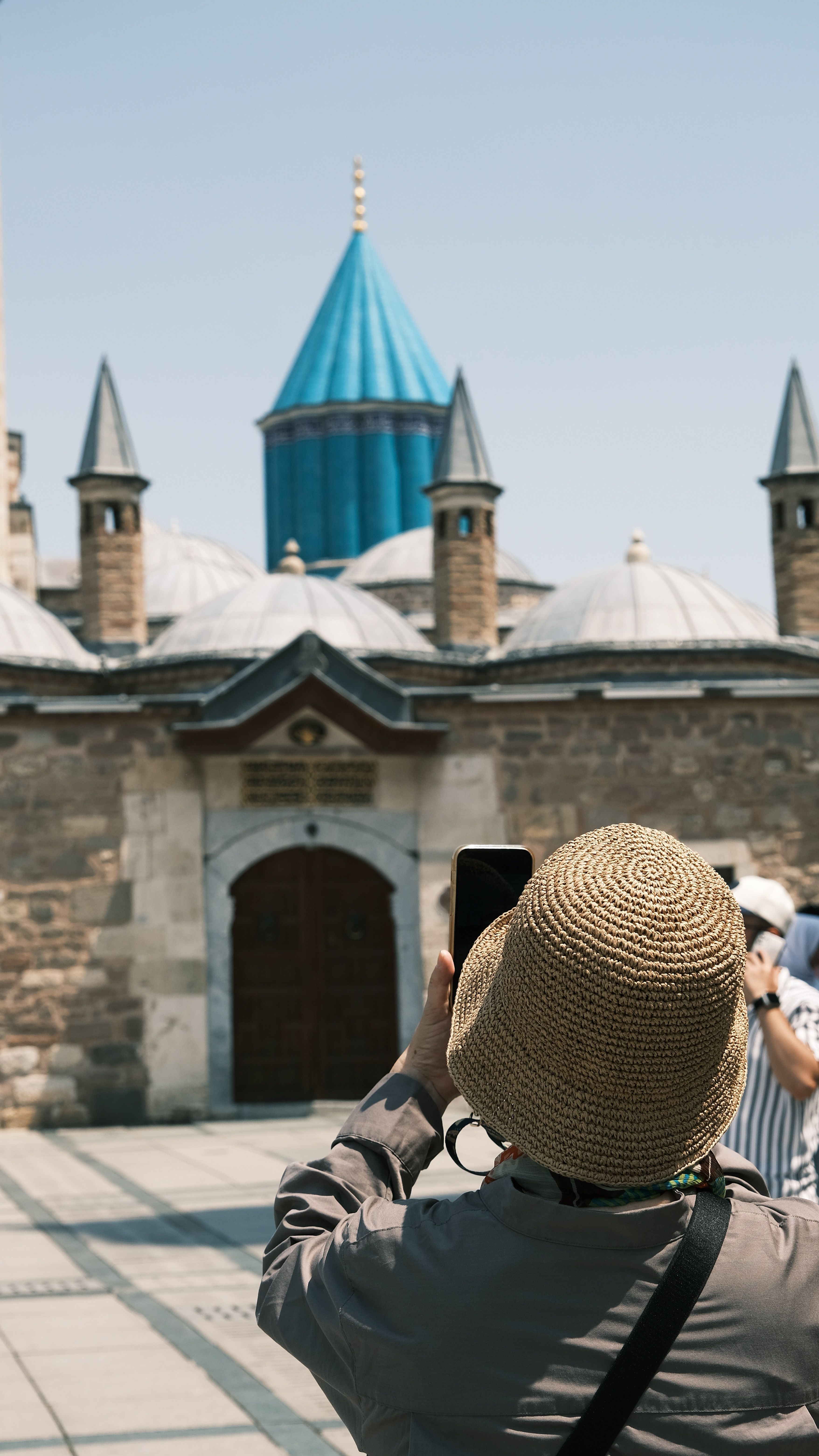 A woman taking a picture of a building with a blue roof · Free Stock Photo