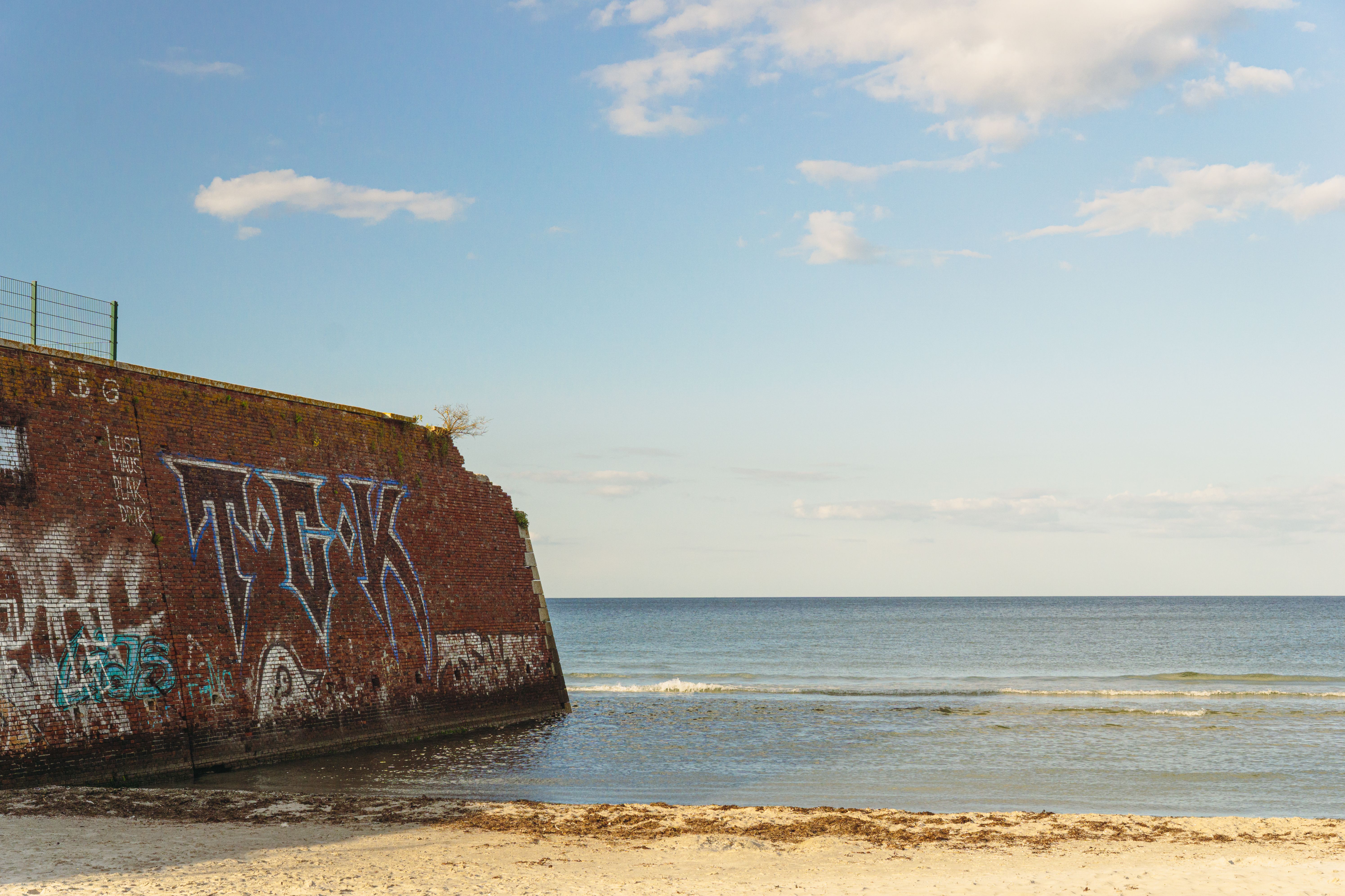 Graffiti on Seaside Brick Wall under Blue Sky · Free Stock Photo