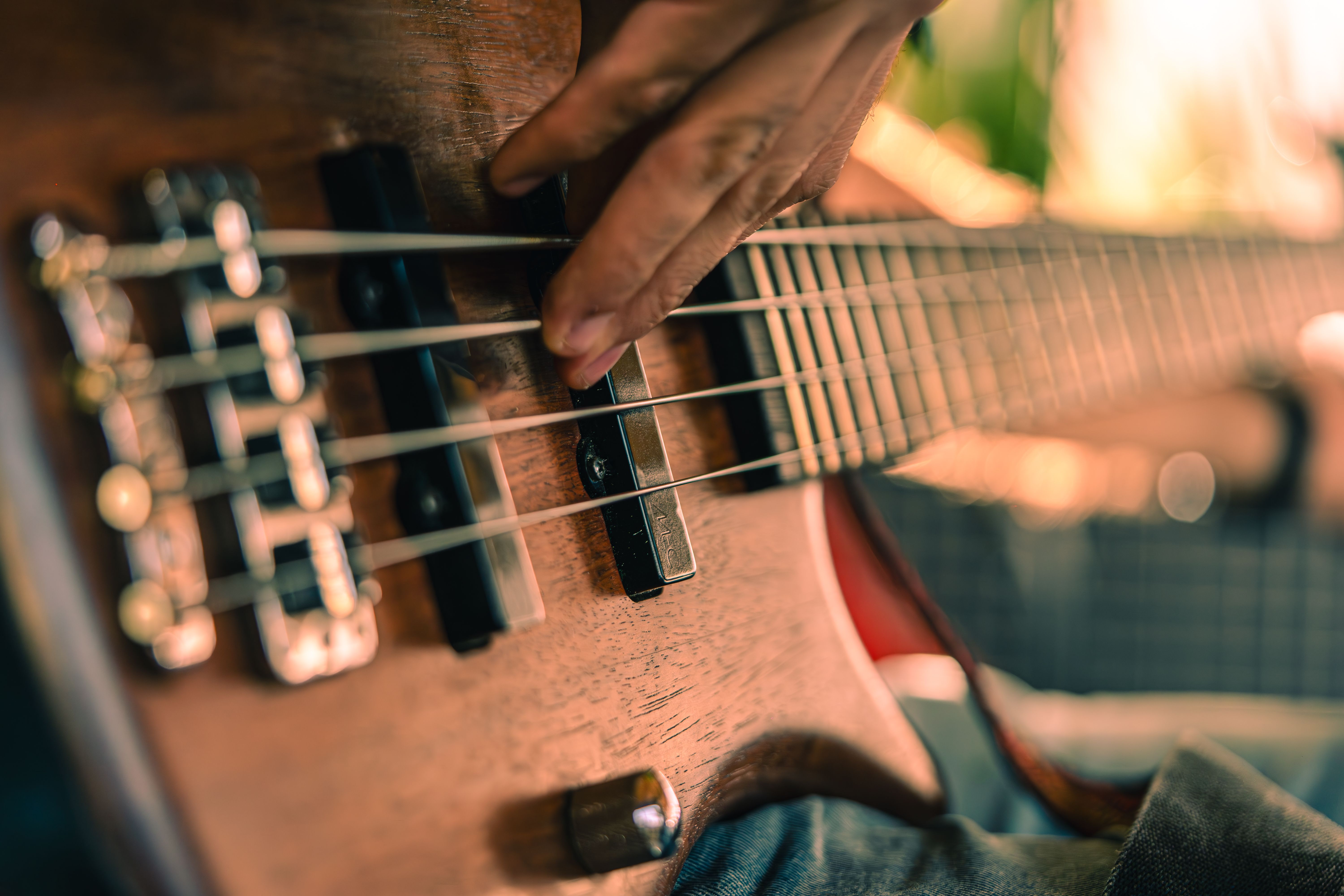 A person playing a bass guitar on a wooden table · Free Stock Photo