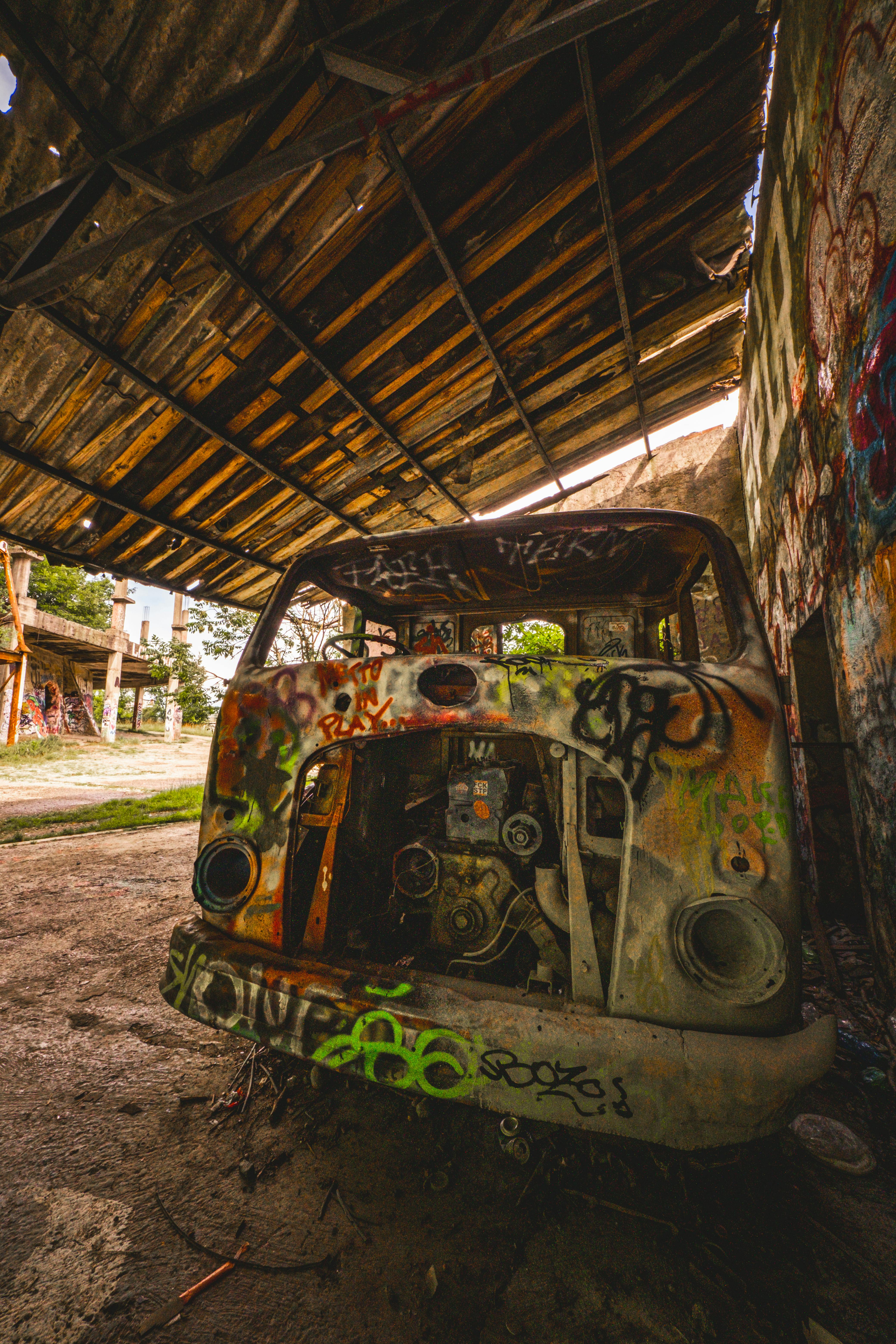 An old rusted bus sits in a garage with graffiti · Free Stock Photo