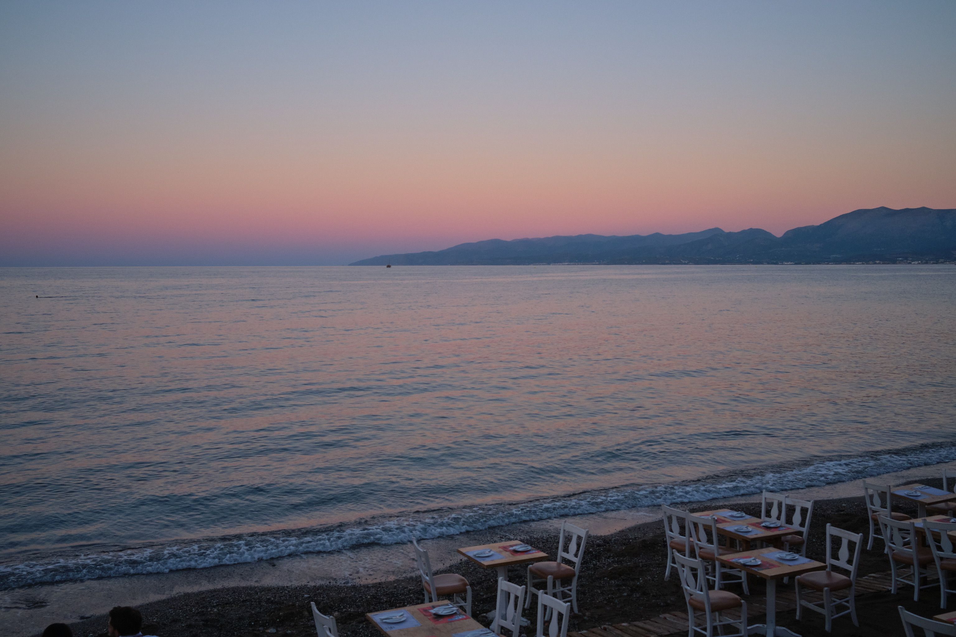 A view of the ocean and a restaurant at sunset · Free Stock Photo