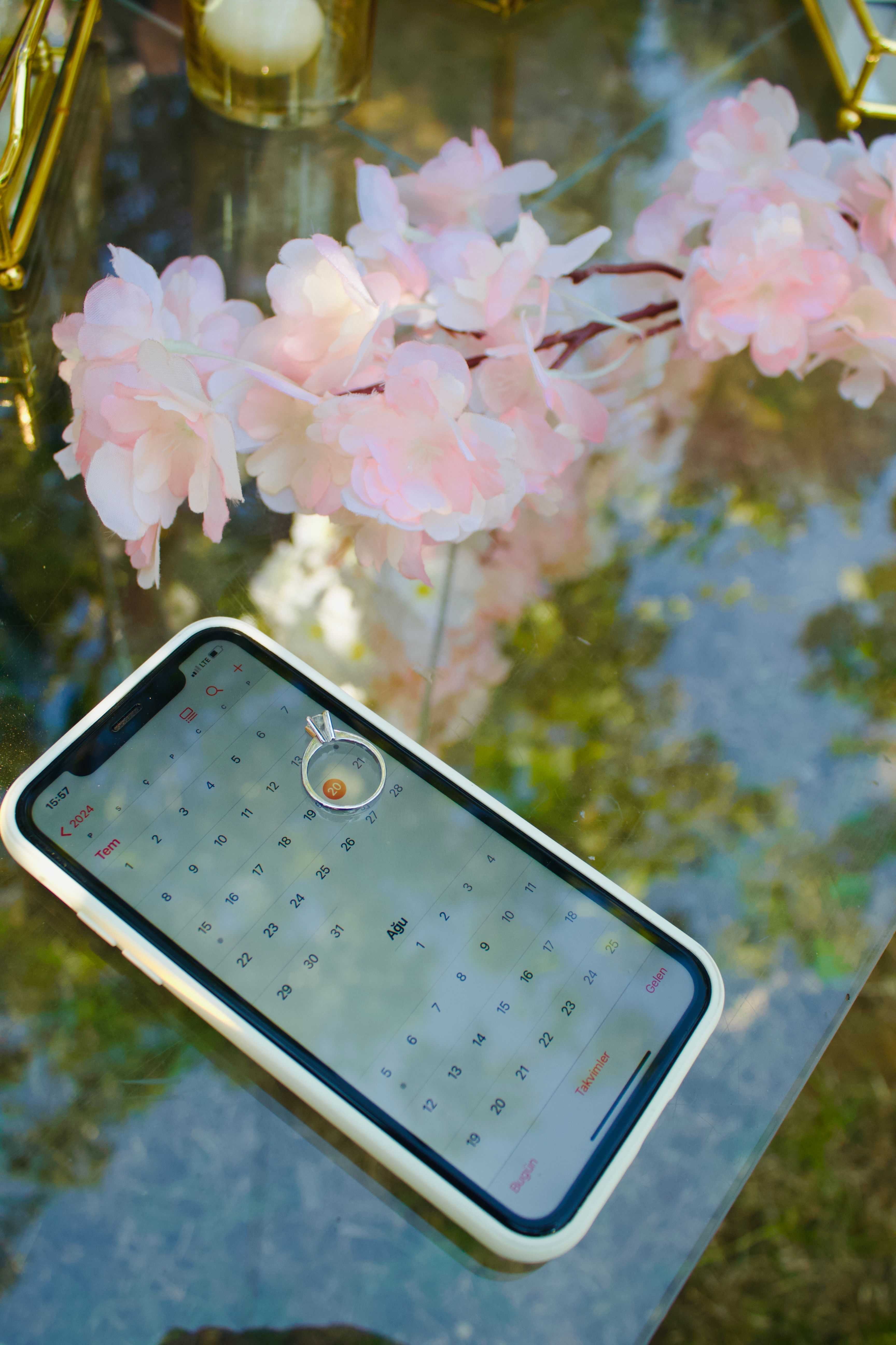 A cell phone is sitting on a table with flowers · Free Stock Photo