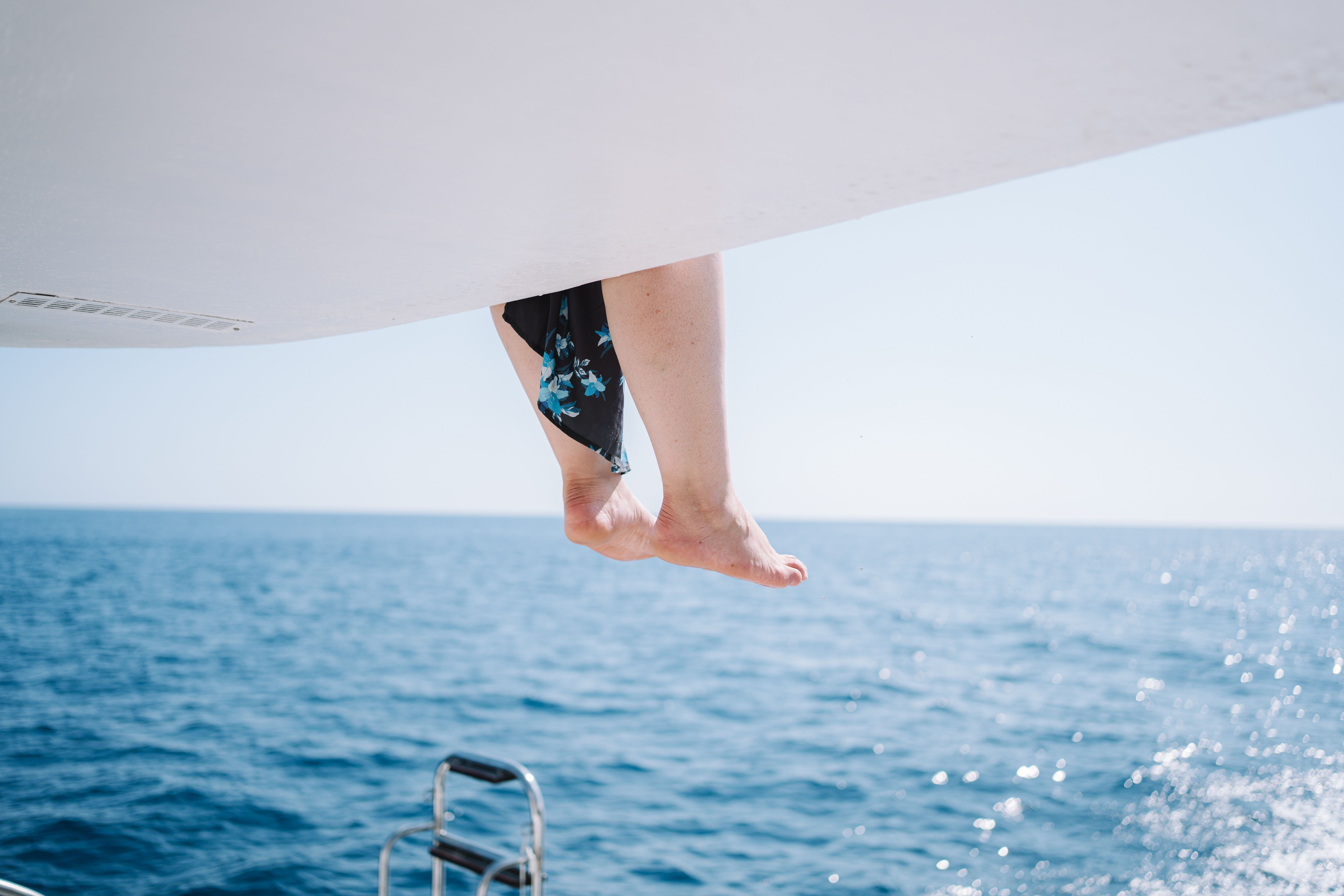 A person's feet are hanging off the side of a boat · Free Stock Photo