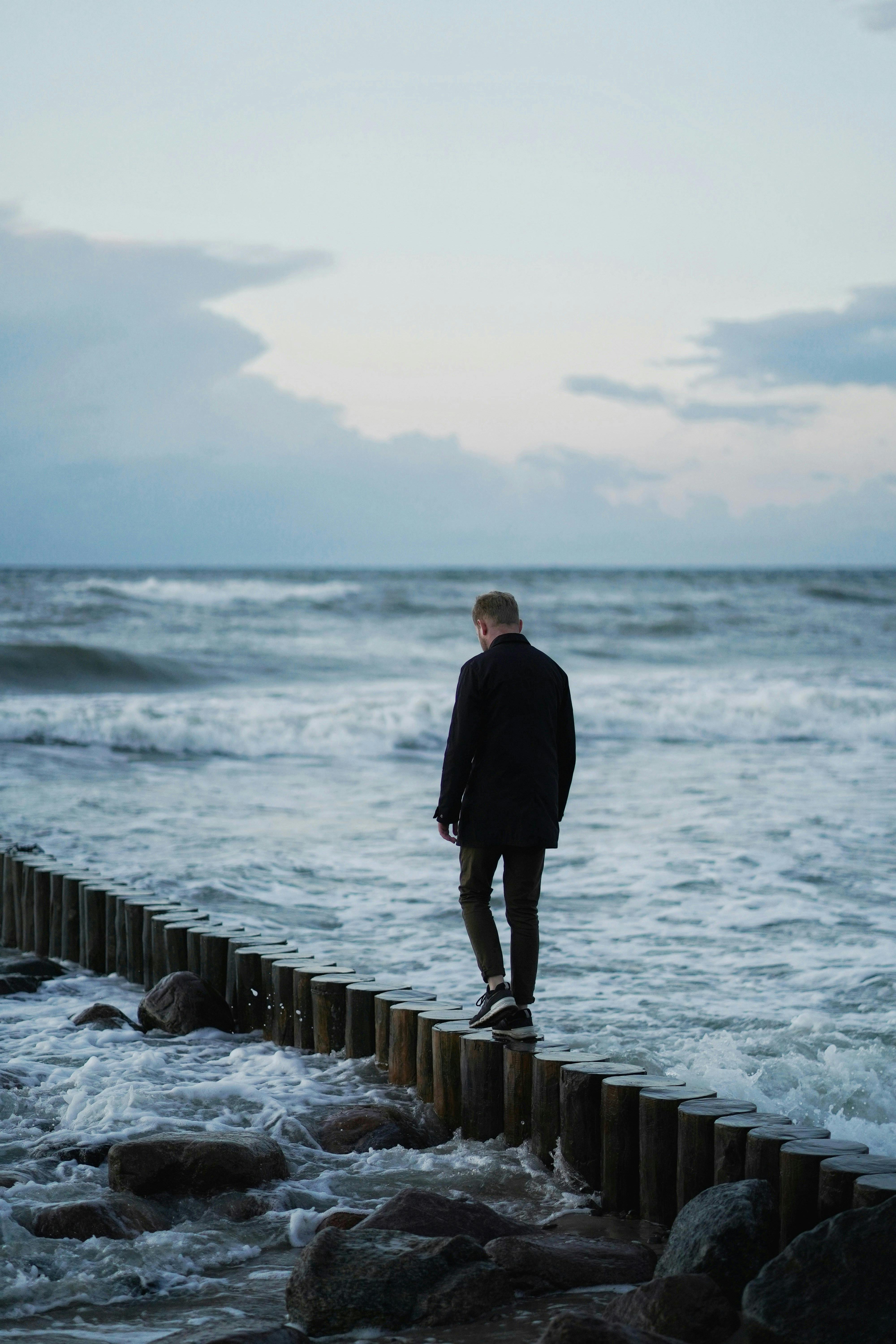 Man Walking on Wooden Breakwater · Free Stock Photo