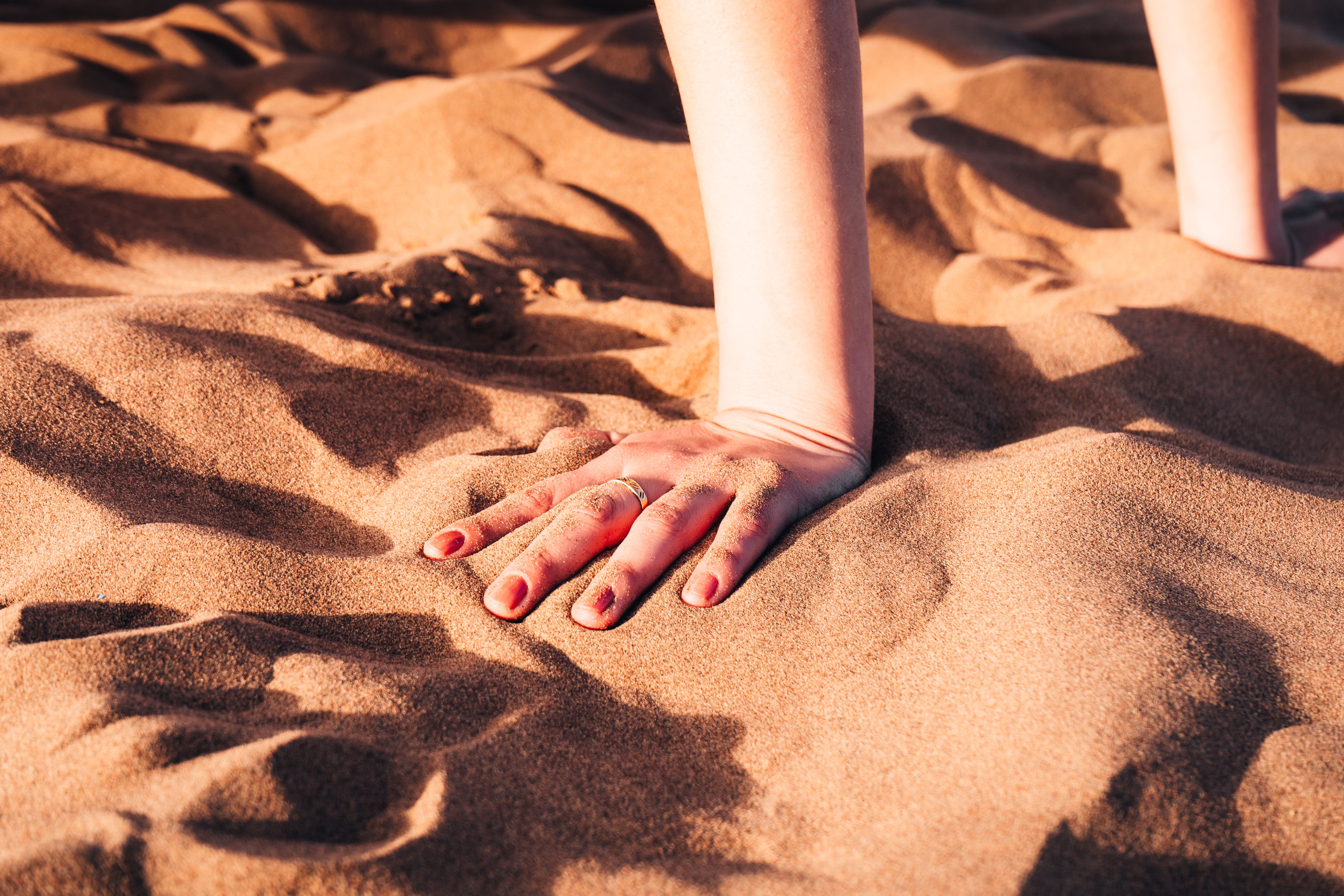 Hand Wearing Wedding Ring Touching Sand · Free Stock Photo