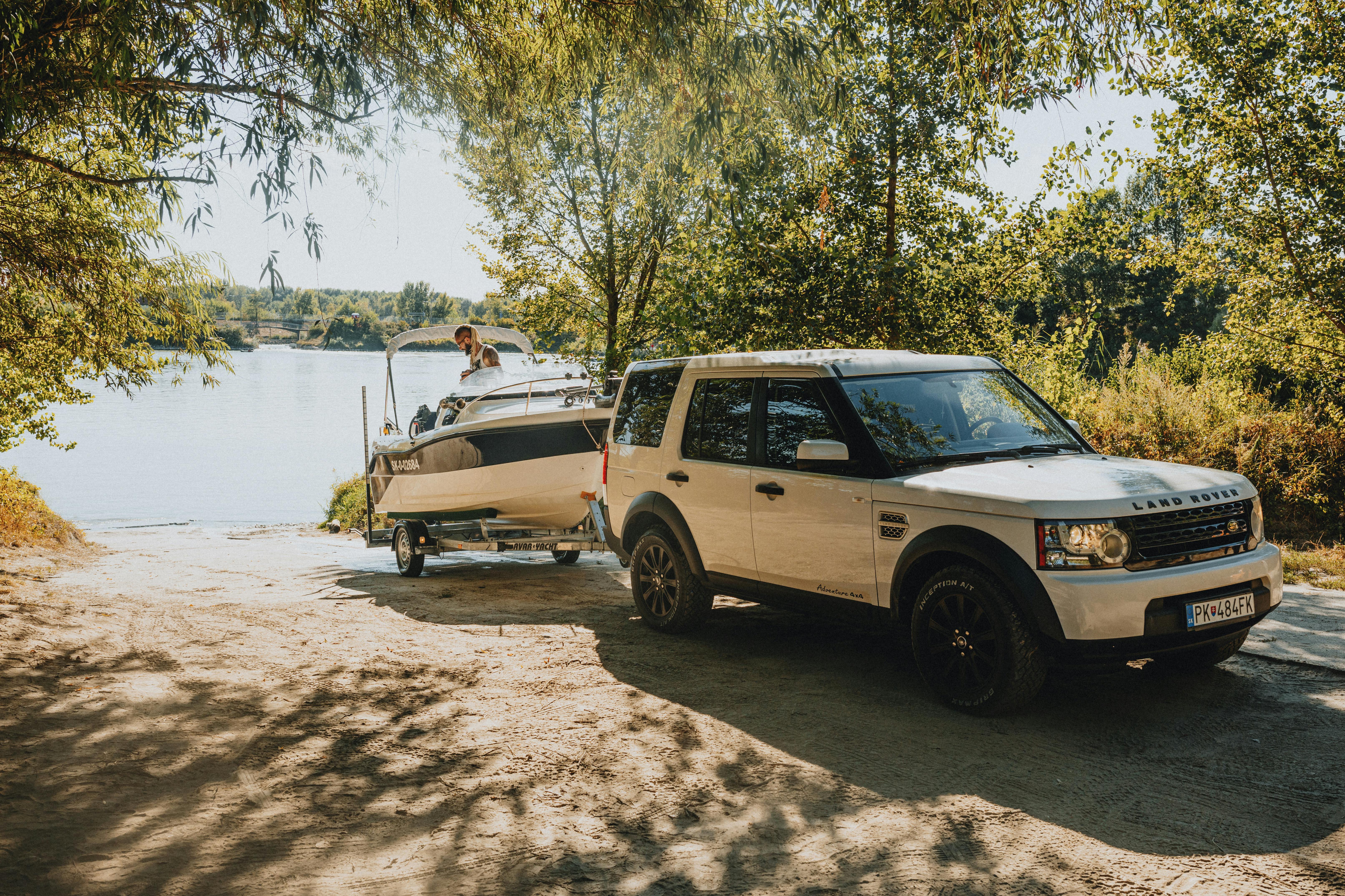 A white suv parked next to a boat · Free Stock Photo