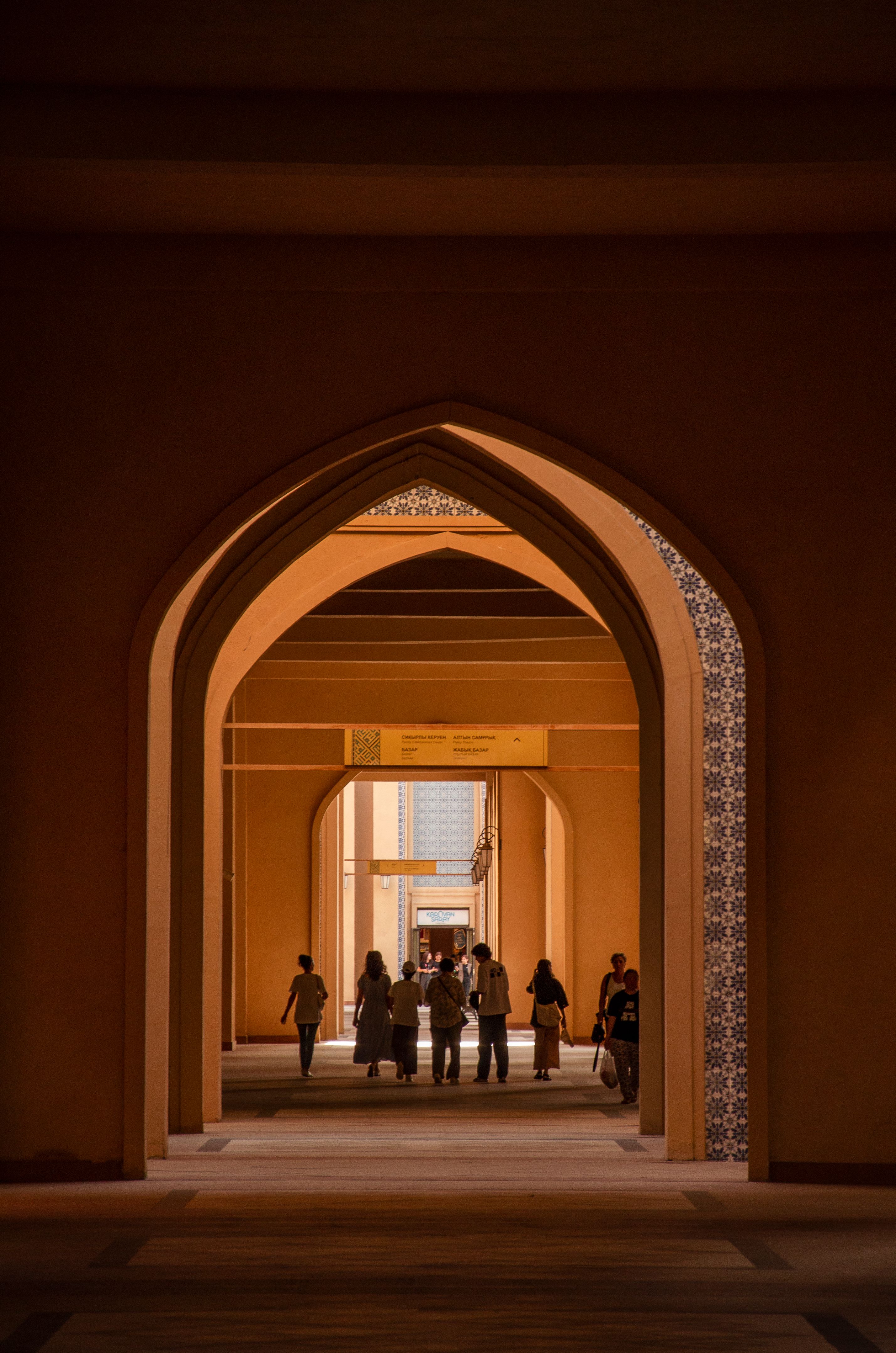 People walk through an archway in a building · Free Stock Photo
