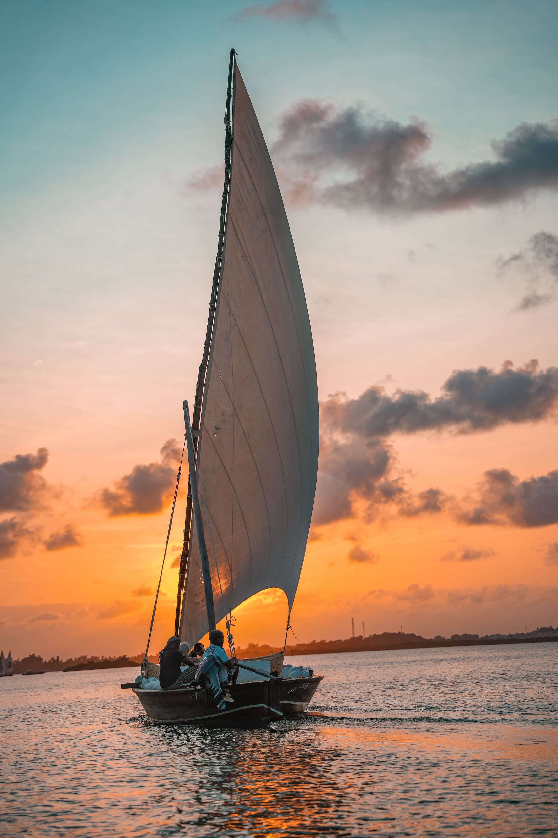 A sailboat is sailing on the water at sunset · Free Stock Photo