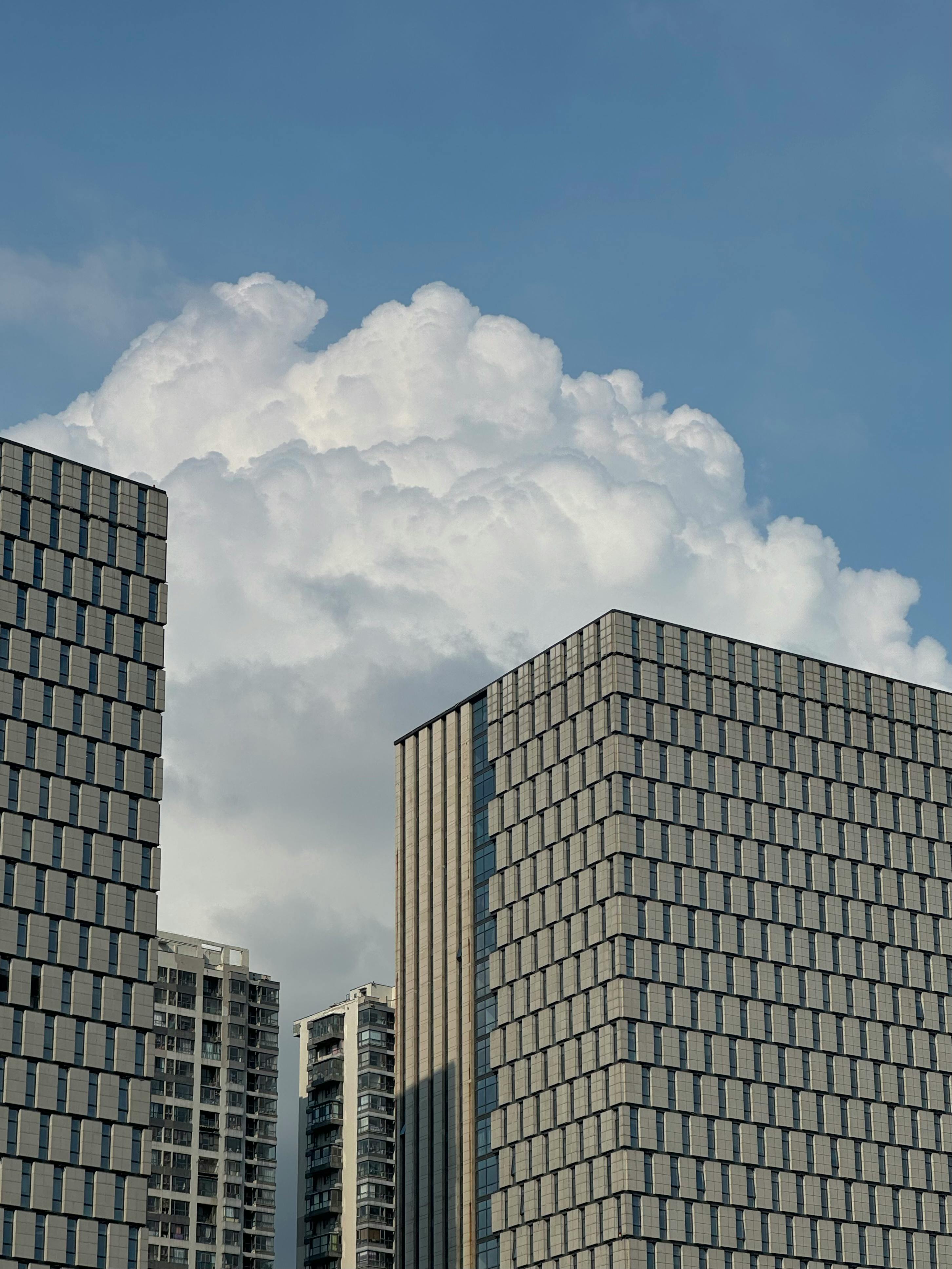 Two tall buildings with clouds in the sky · Free Stock Photo