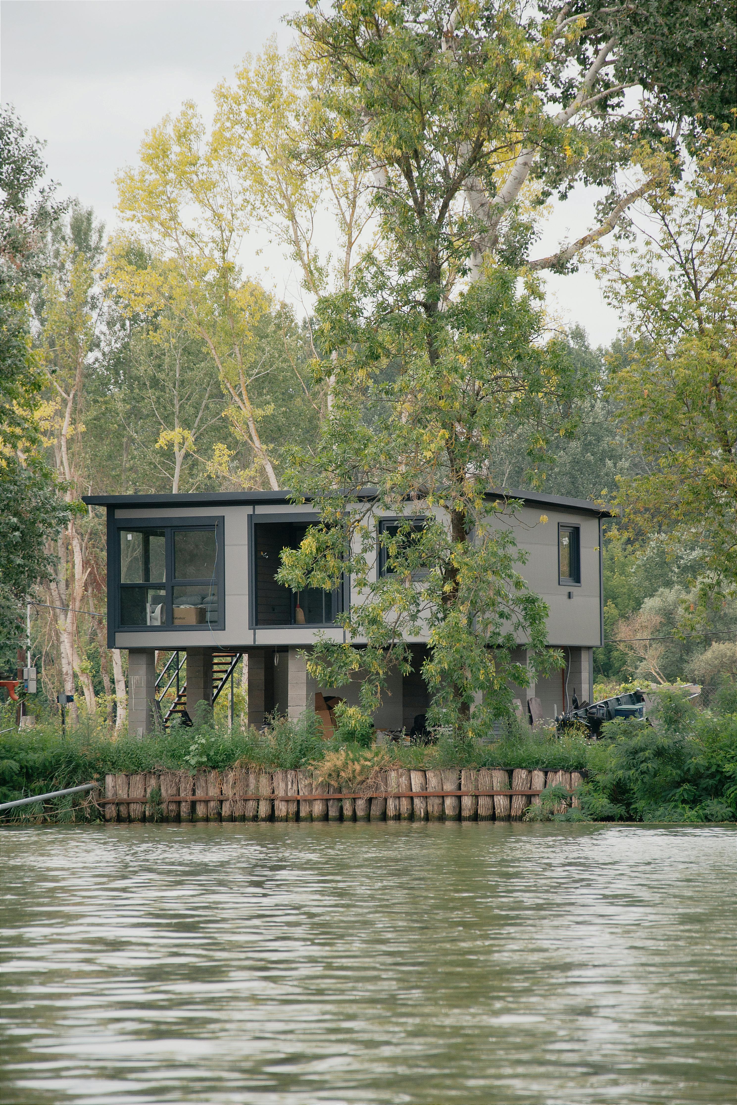 A house on the water with trees in the background · Free Stock Photo