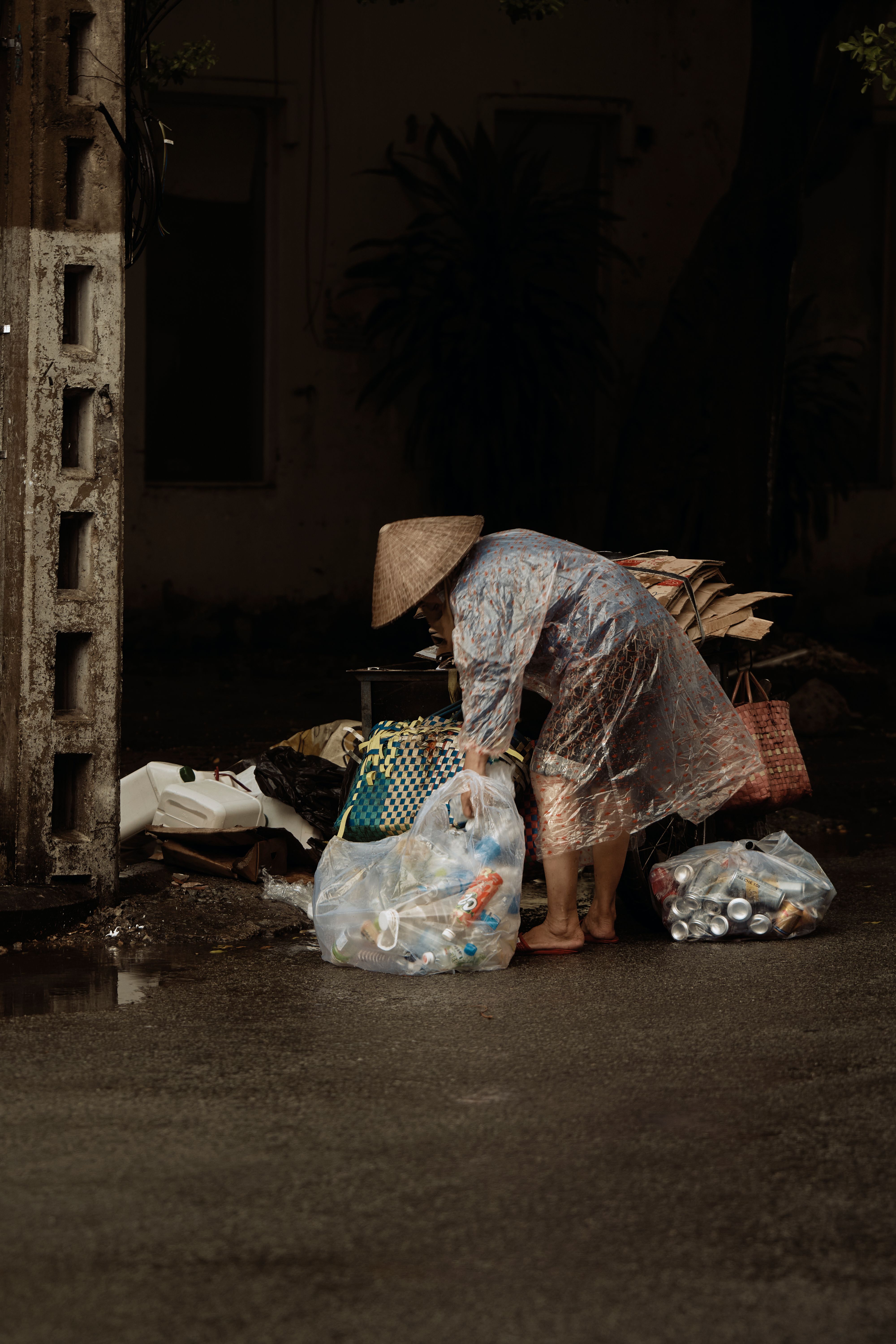 A woman is standing in the rain with a bag of trash · Free Stock Photo