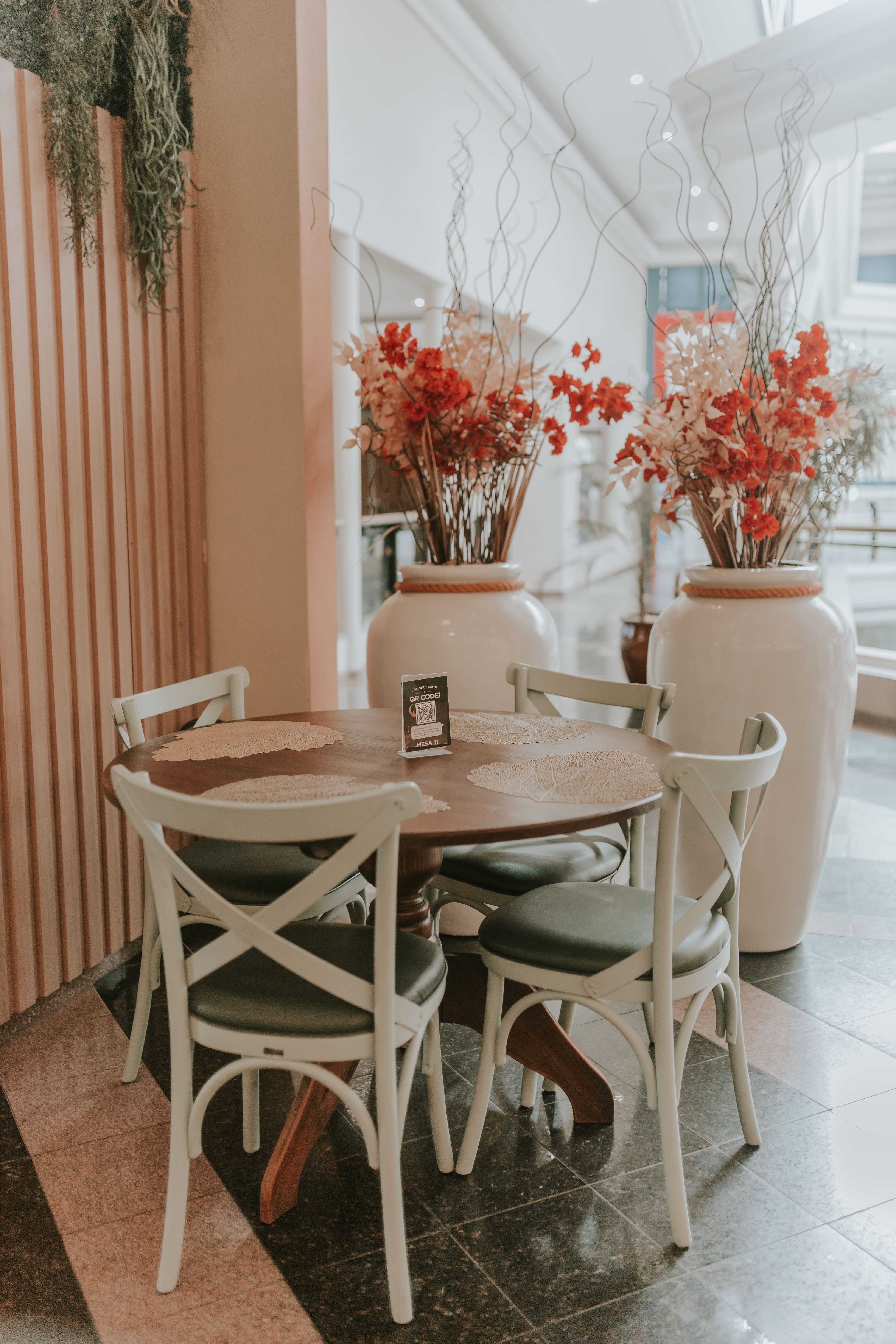 A table and chairs in a restaurant with vases of flowers · Free Stock Photo