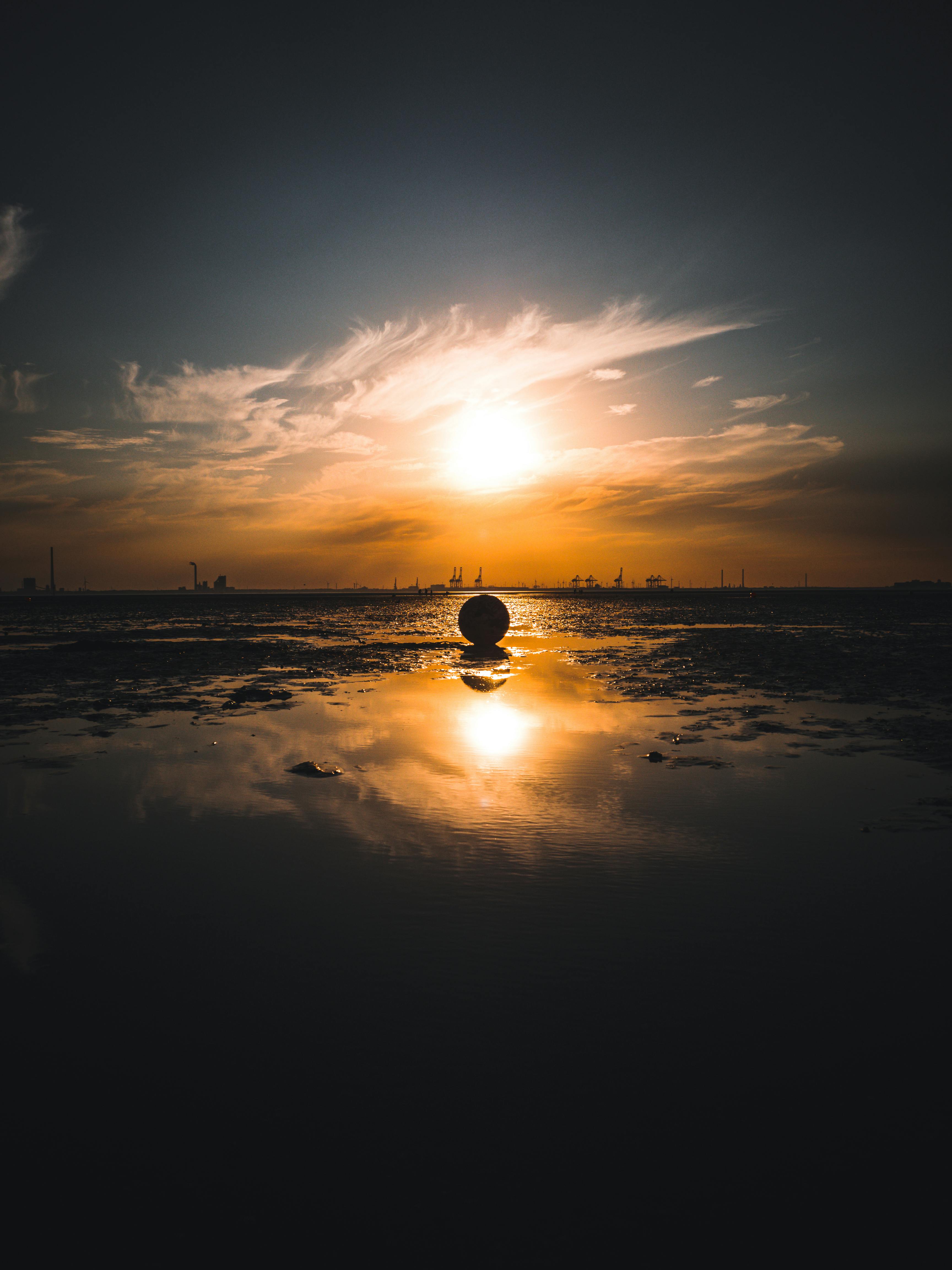 A ball is floating in the water at sunset · Free Stock Photo