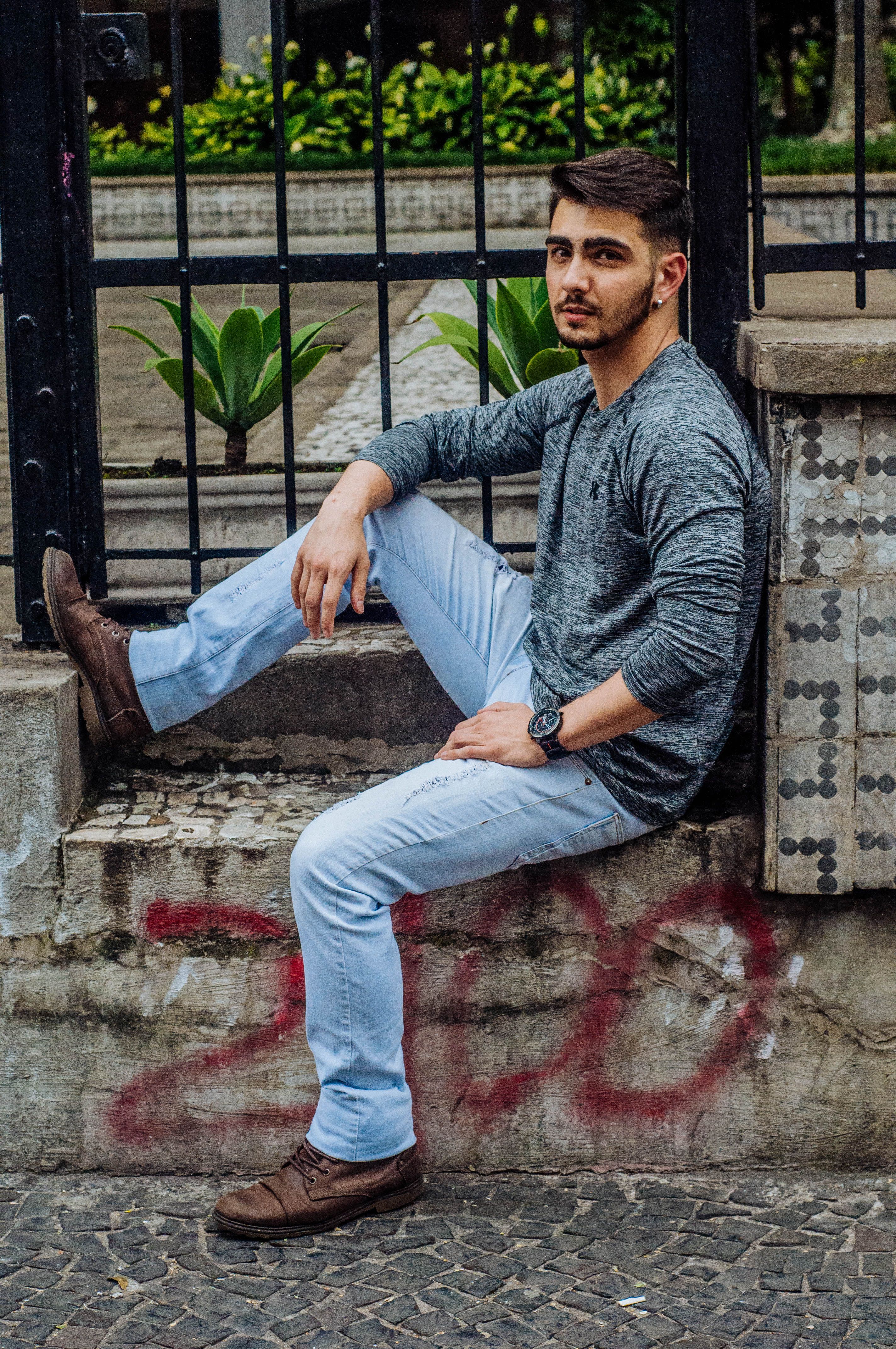 A man sitting on a ledge with graffiti on the wall · Free Stock Photo
