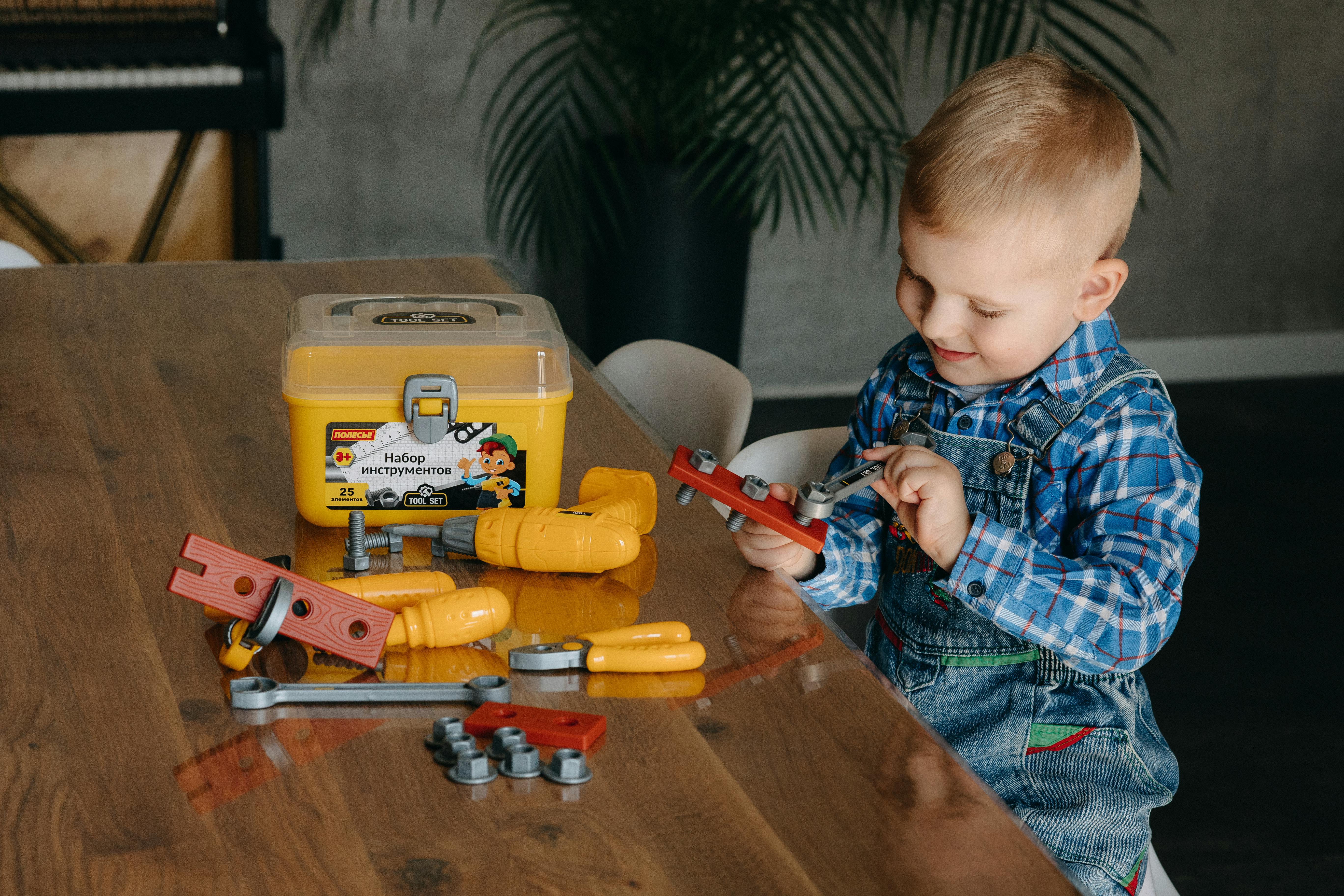 A young boy playing with tools on a table · Free Stock Photo