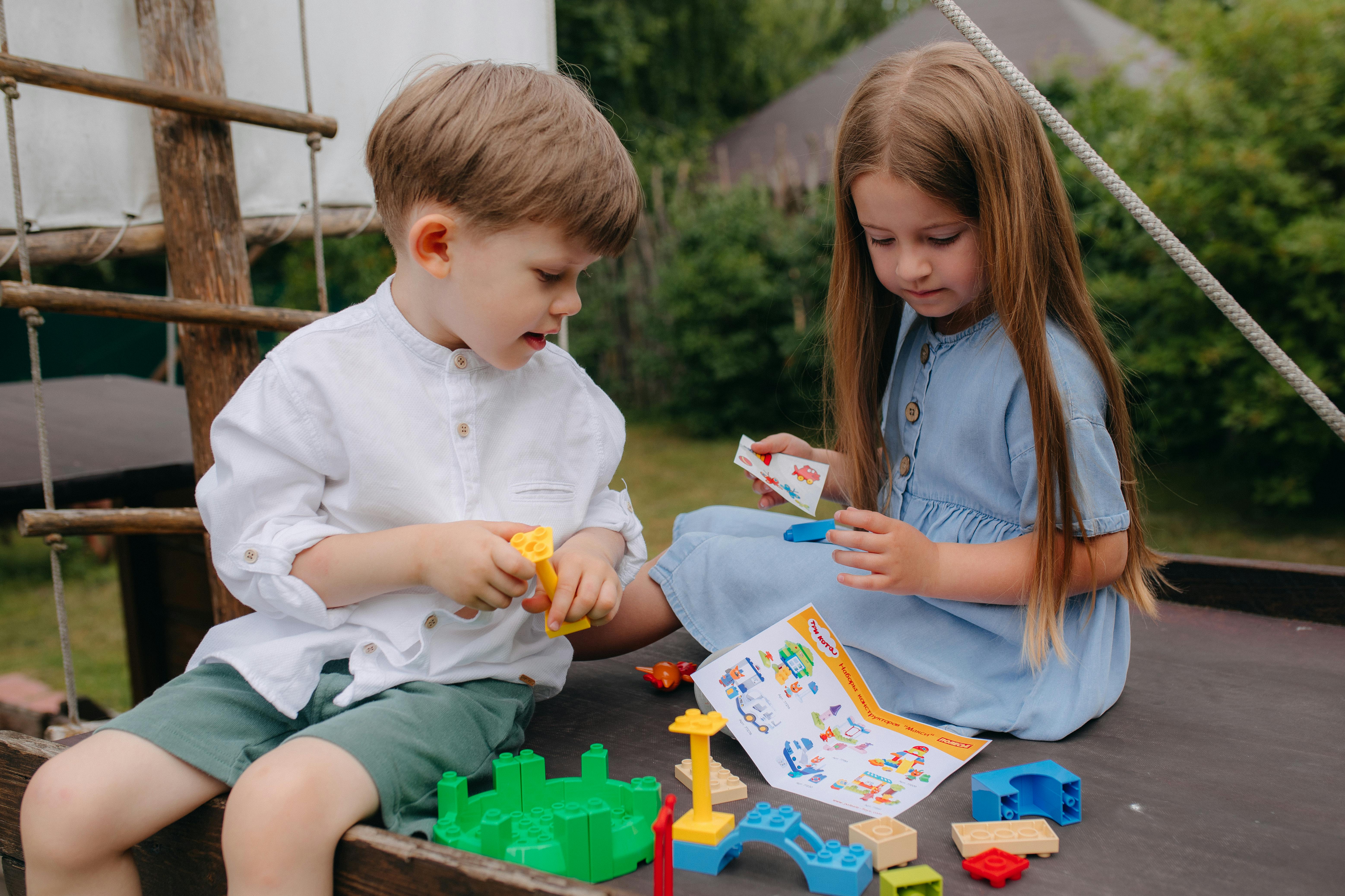 Two children playing with toys on a wooden deck · Free Stock Photo