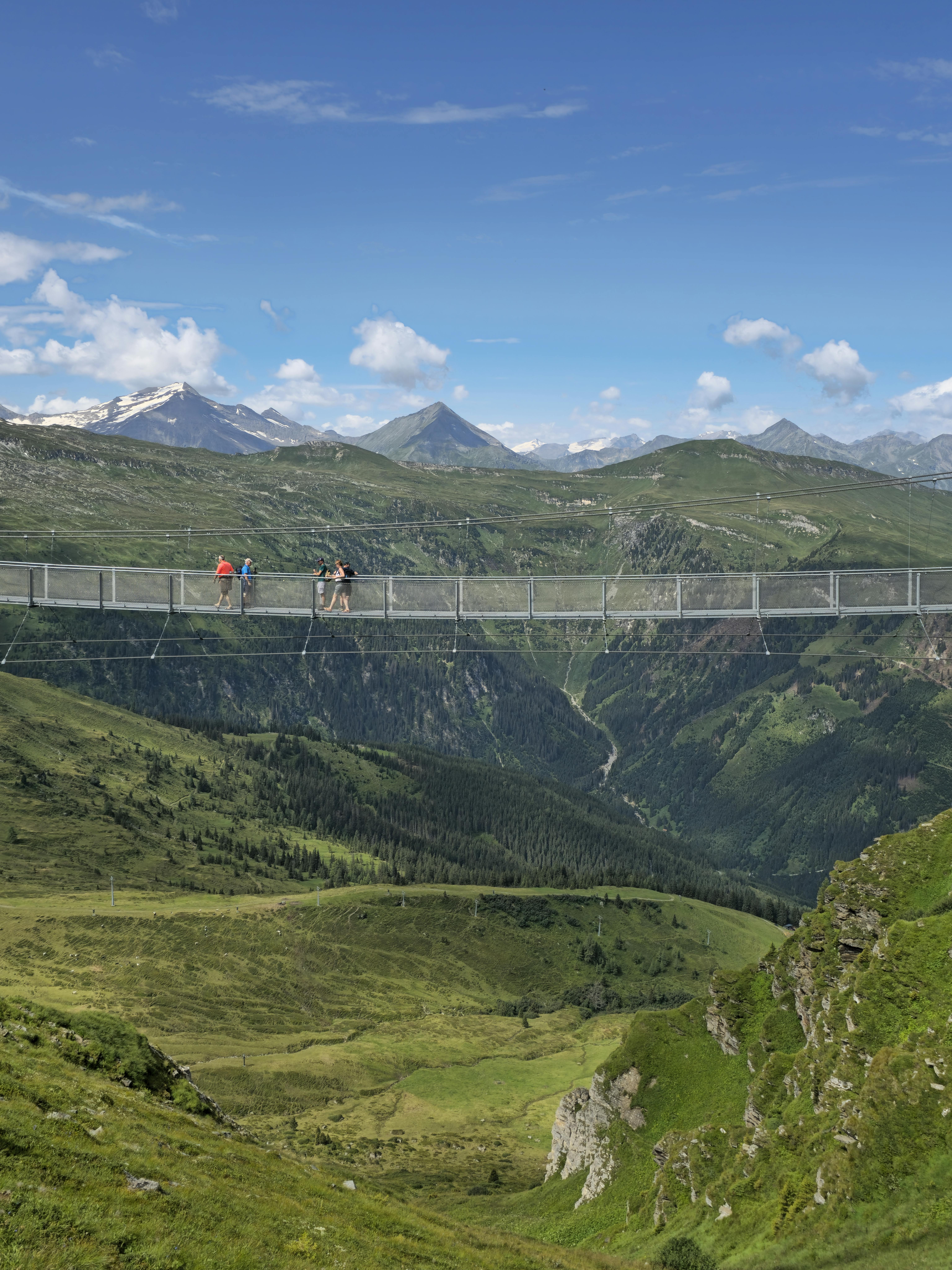 A person walking on a suspension bridge over a valley · Free Stock Photo