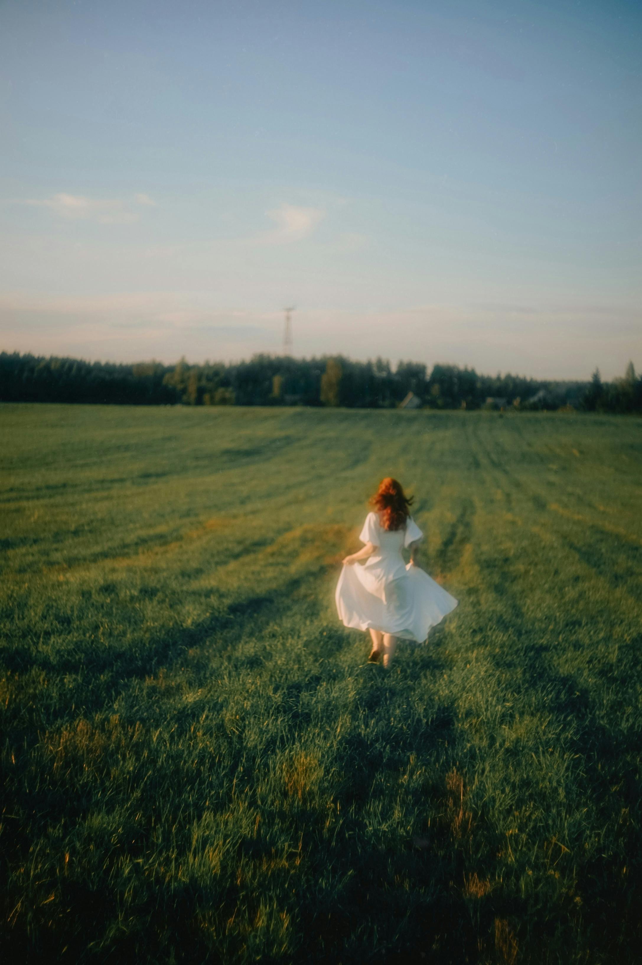 A girl in a white dress running through a field · Free Stock Photo