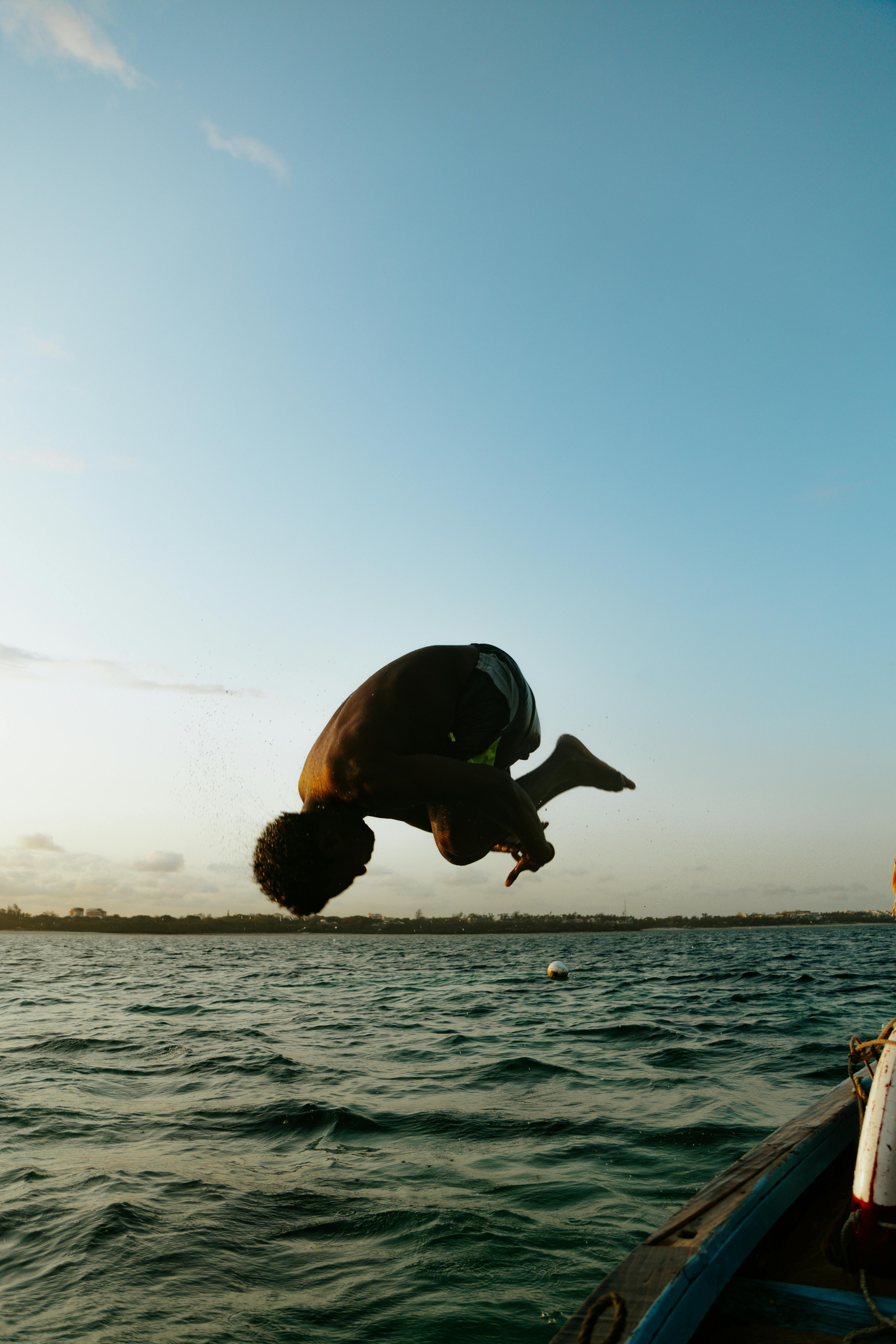 A man diving into the water from a boat · Free Stock Photo