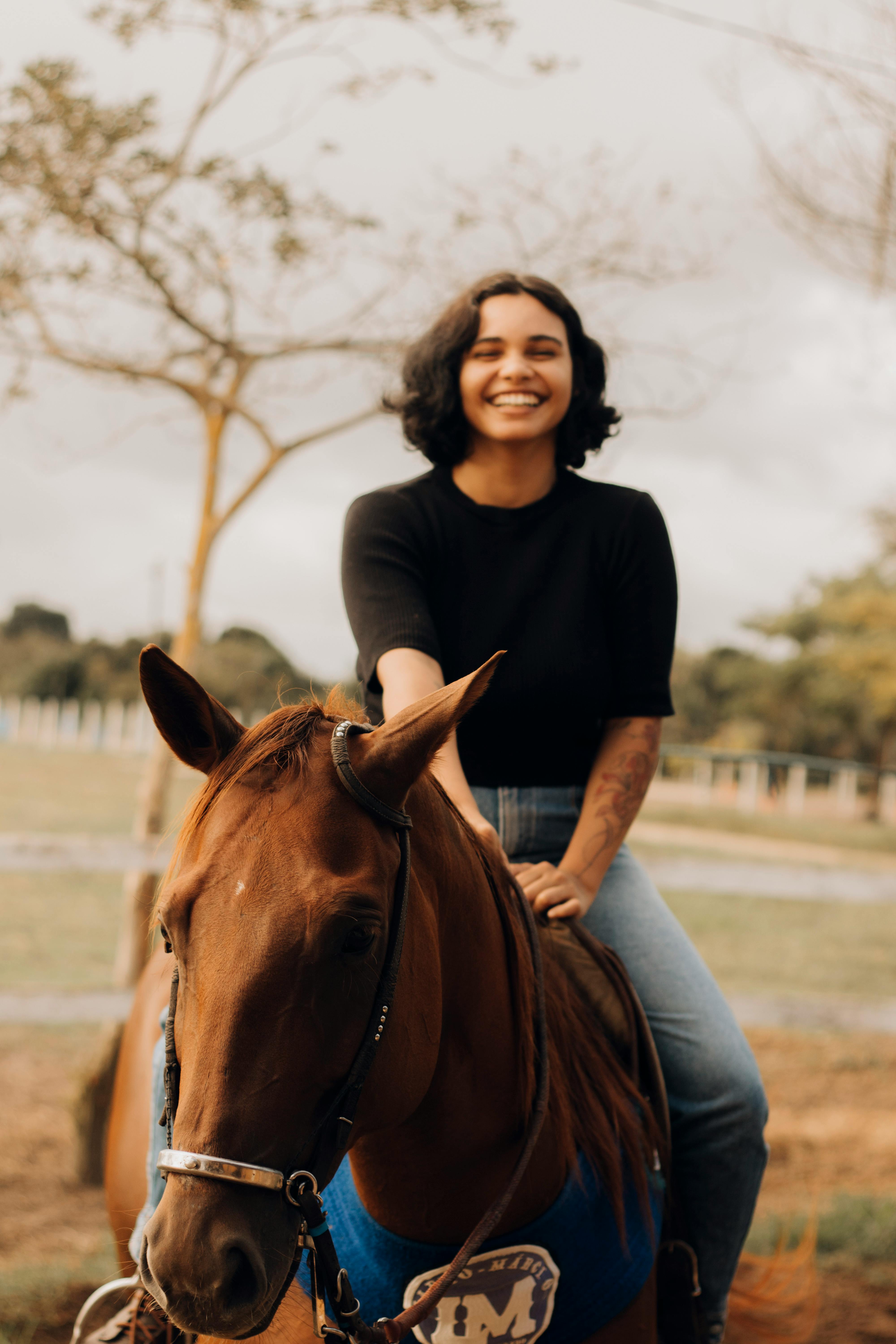 A woman smiling while riding a horse · Free Stock Photo